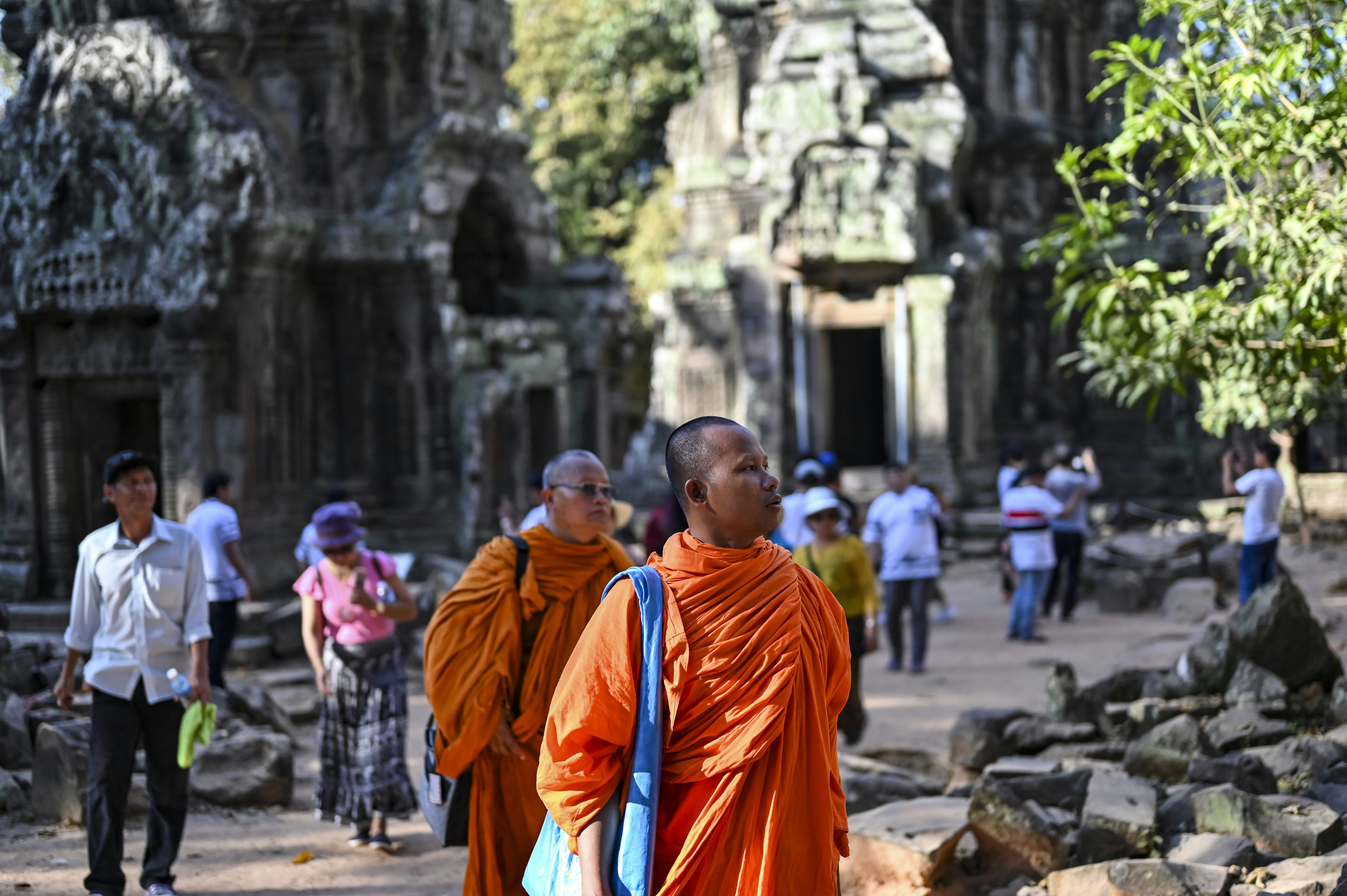 Monk in Orange Robes Walks Through Ancient Temple Grounds