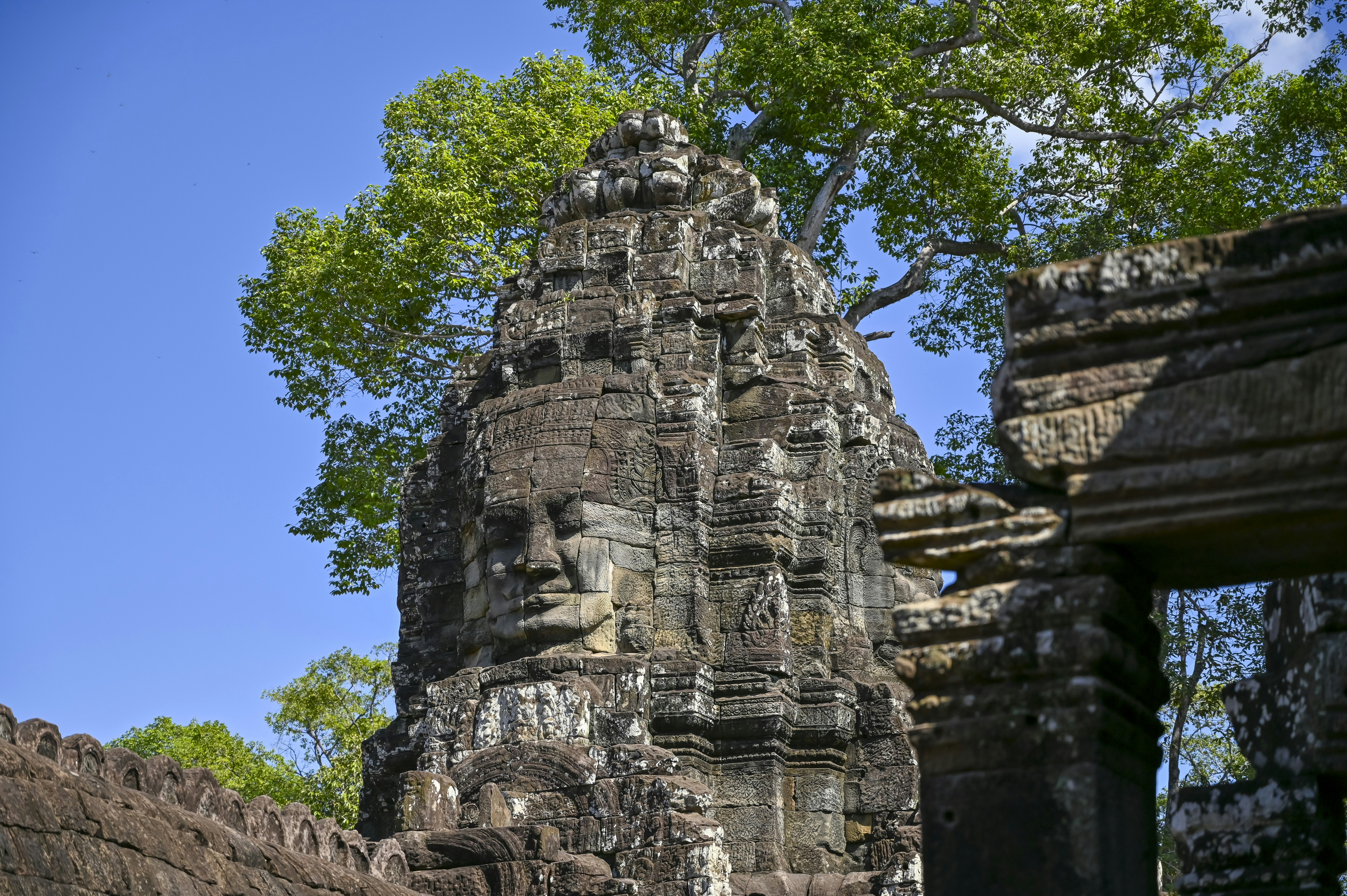 Guardians of the Stone: A Carved Face Amid Khmer Ruins