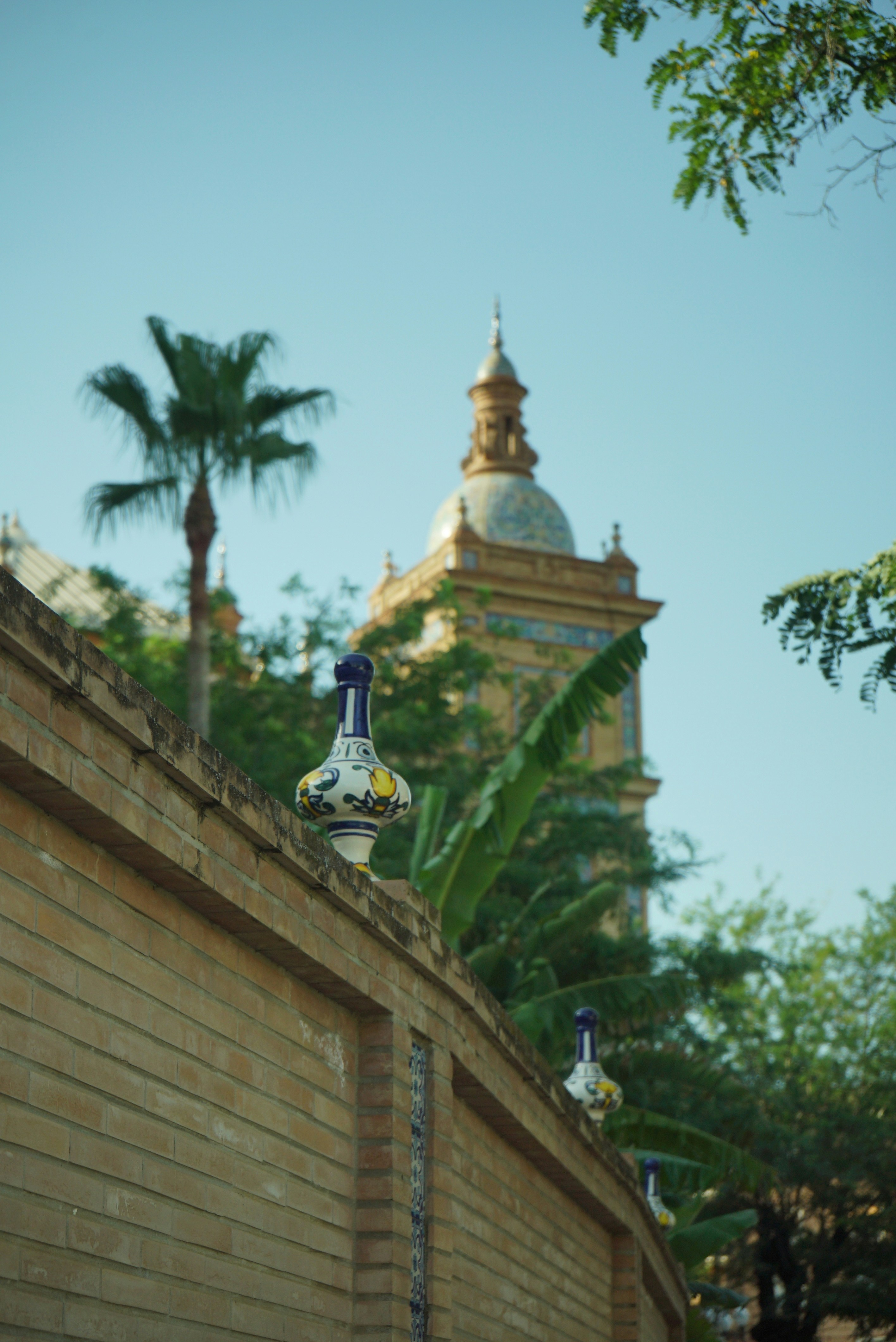 Ornamental Vase on a Sunlit Brick Wall with a Towered Retreat in the Background