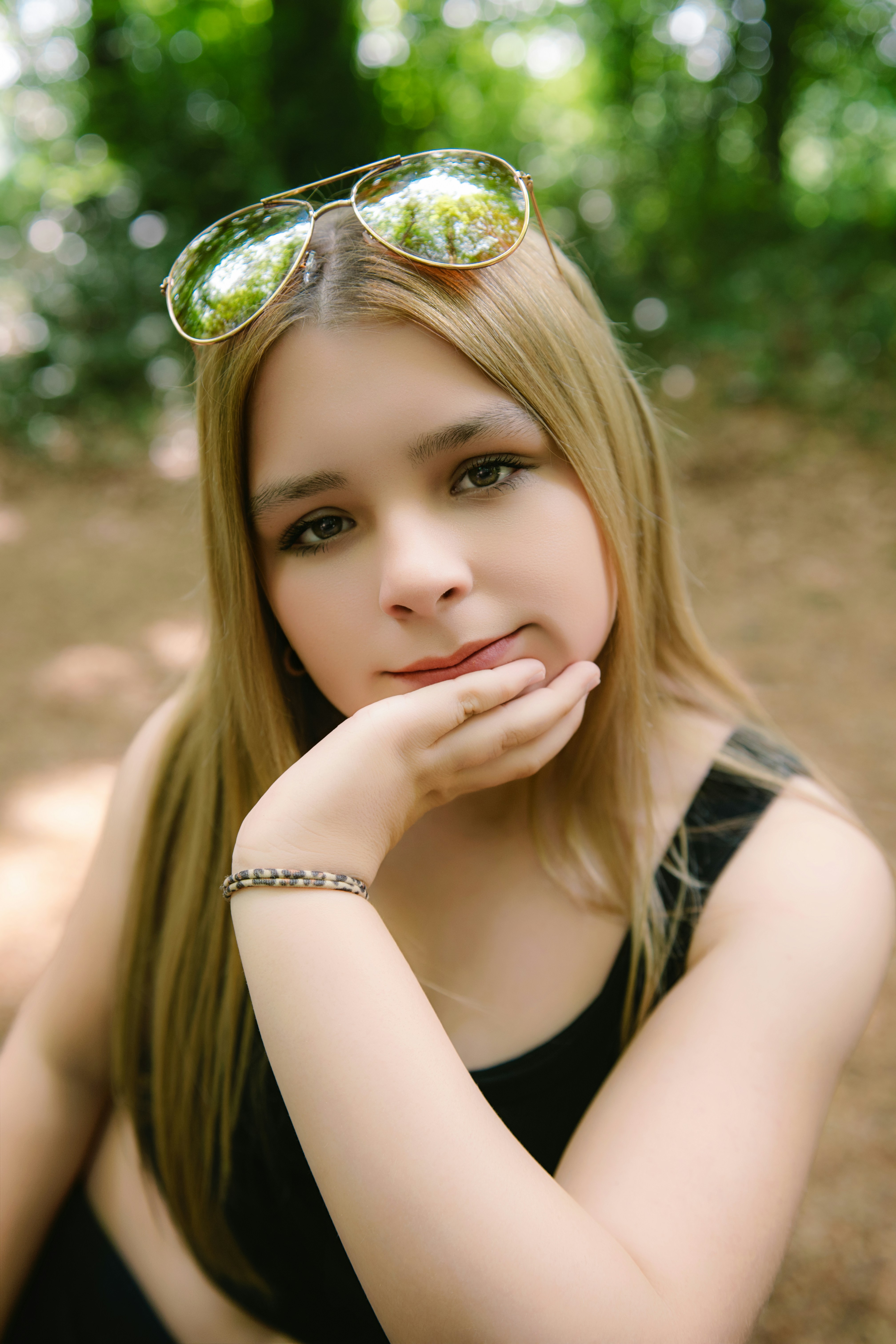 Soft gaze in the park: a sunlit portrait with reflective aviators