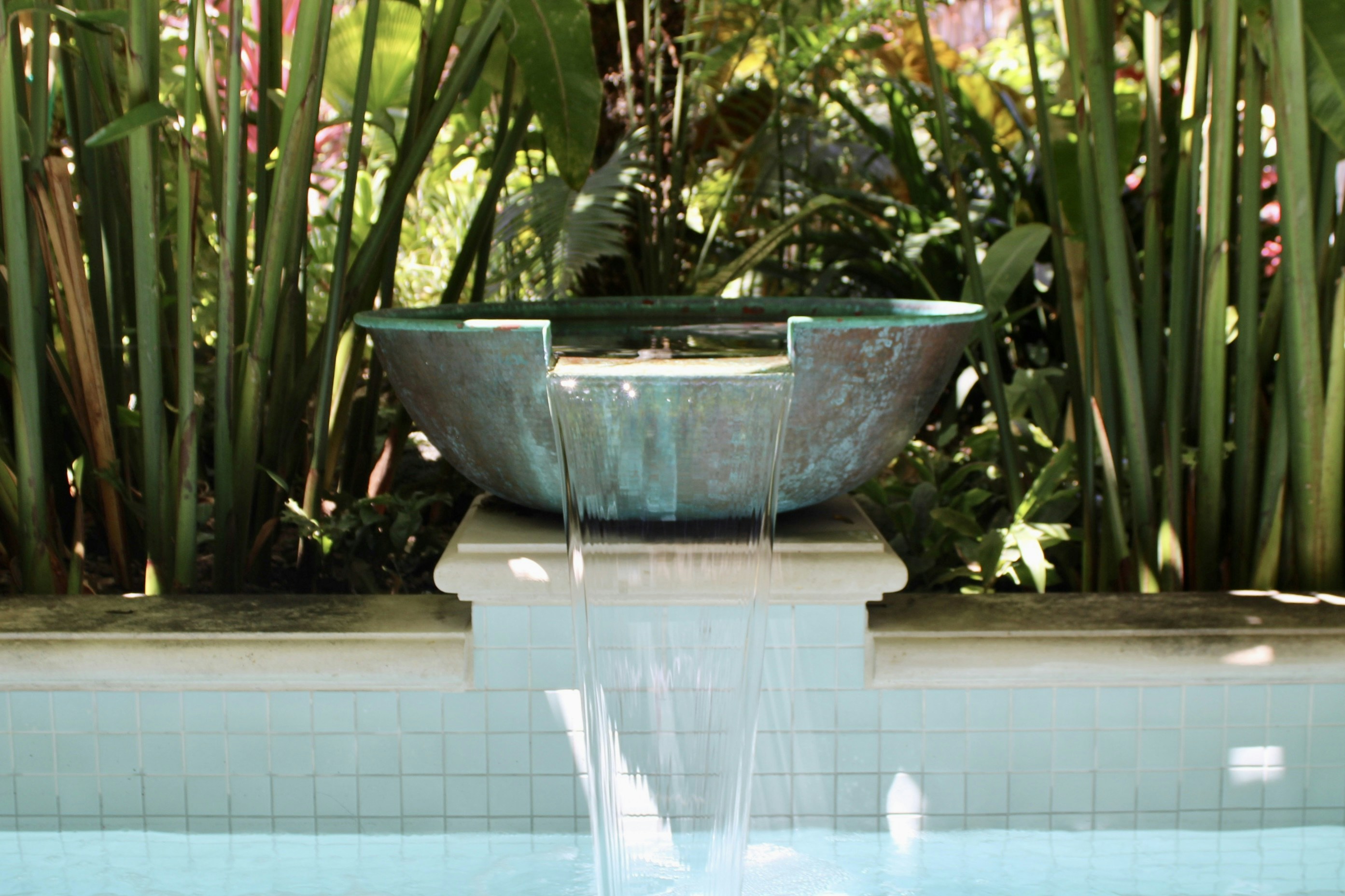 Ceramic fountain bowl over a sunlit pool