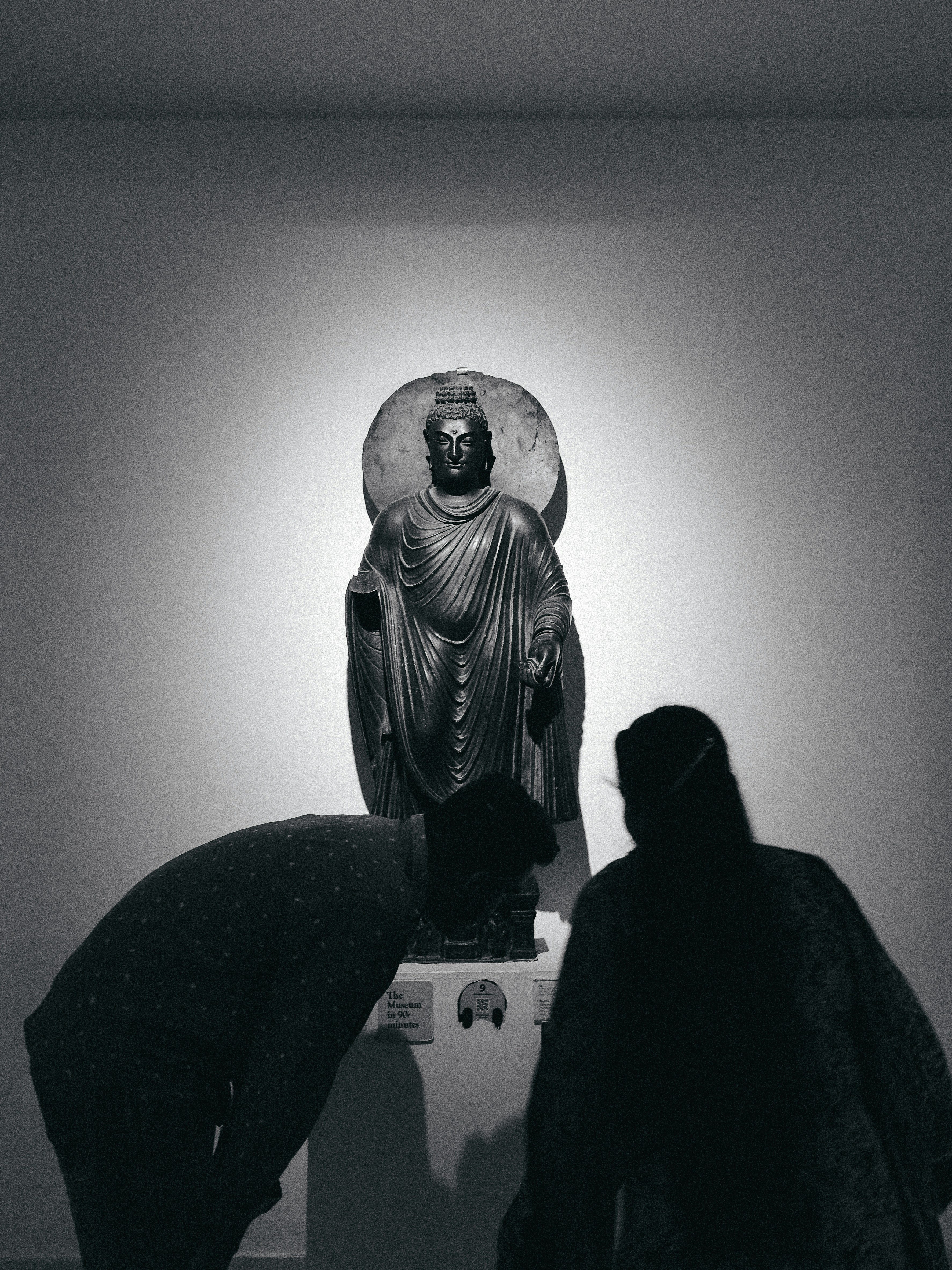 Silhouette of Reverent Visitors Before a Standing Buddha