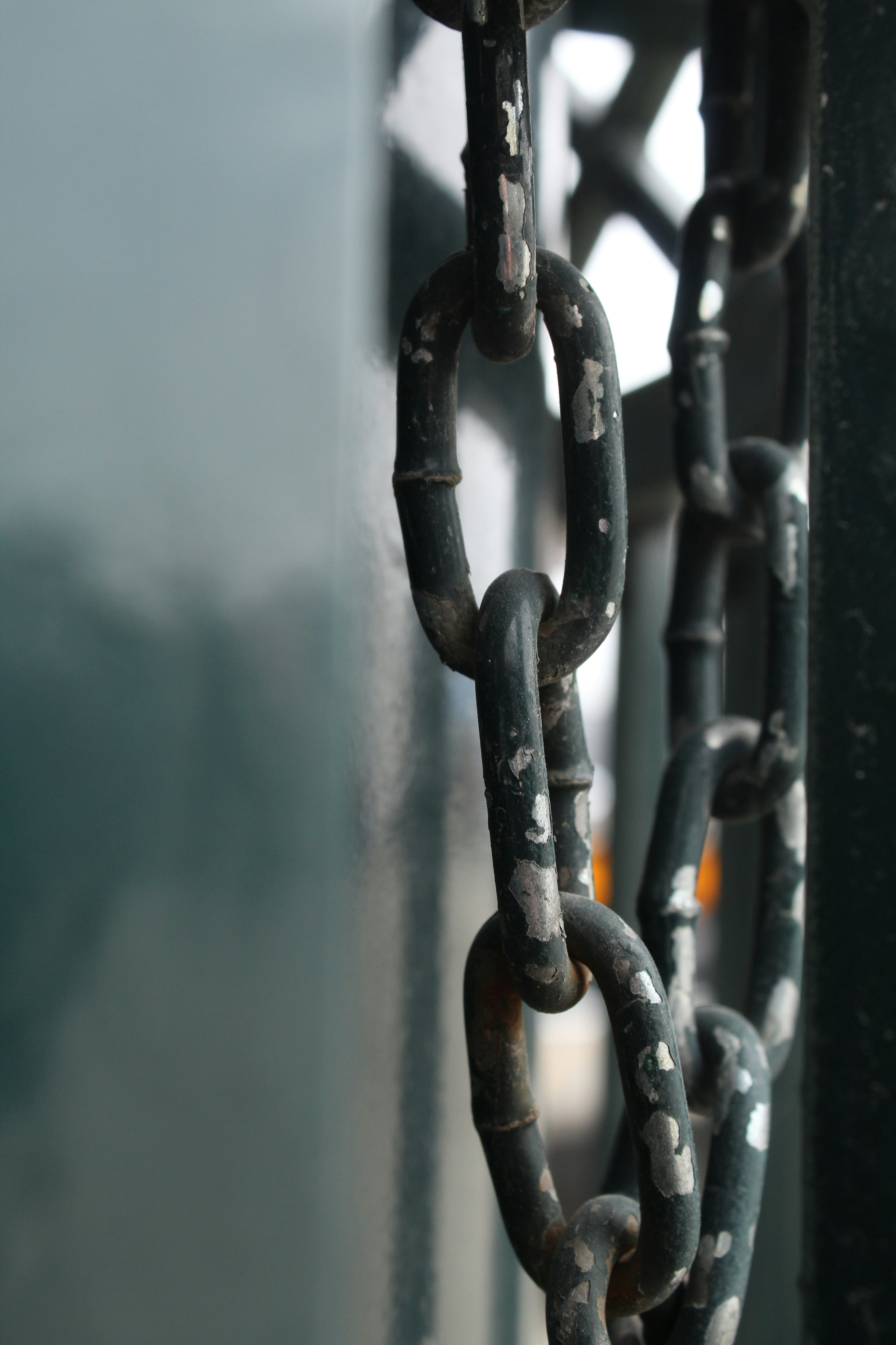 Close-up of weathered metal chains against a dark, industrial backdrop, emphasizing texture and patina with shallow depth of field.