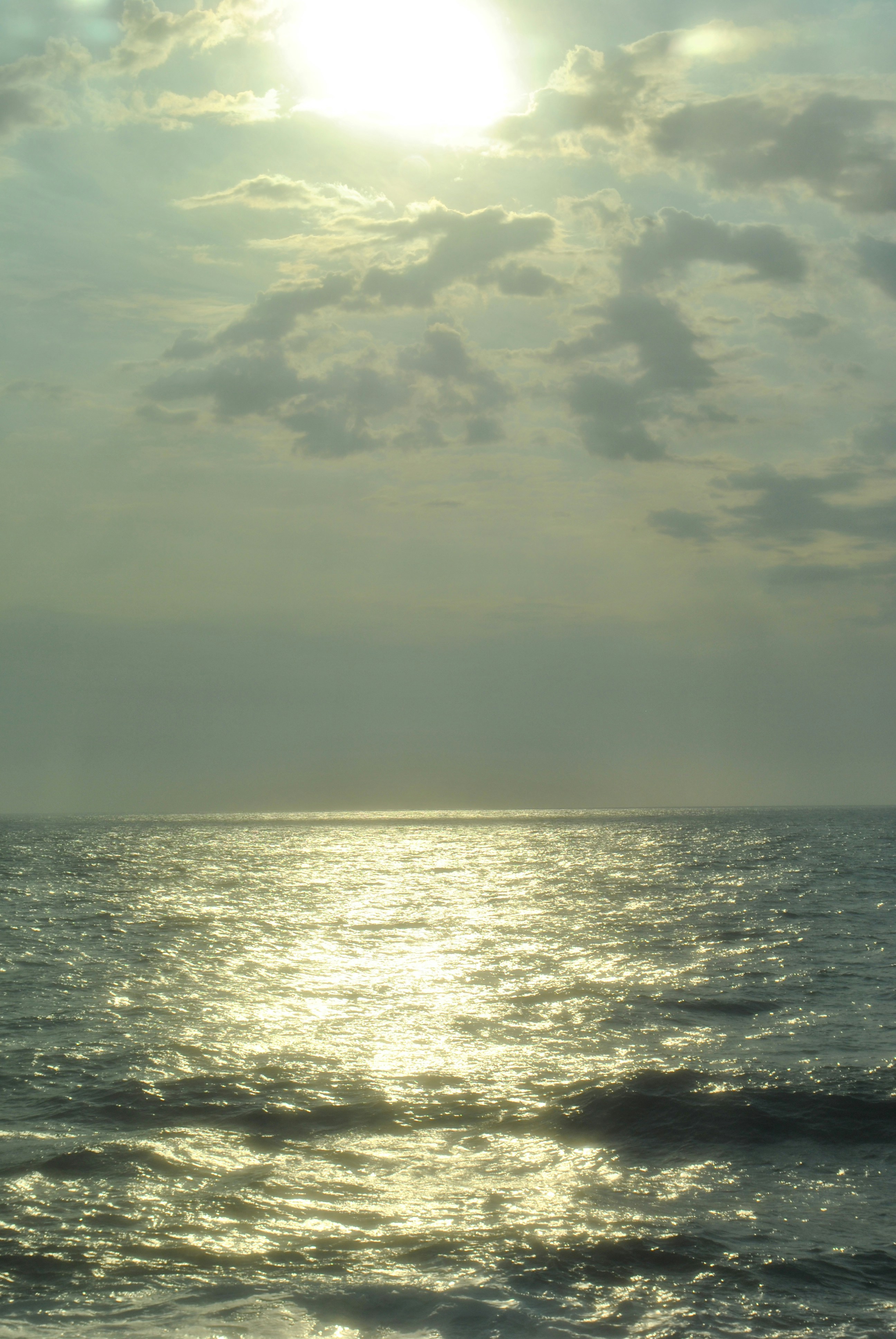 Glassy Horizon: Sunlit Sea Under Soft Cloudveil