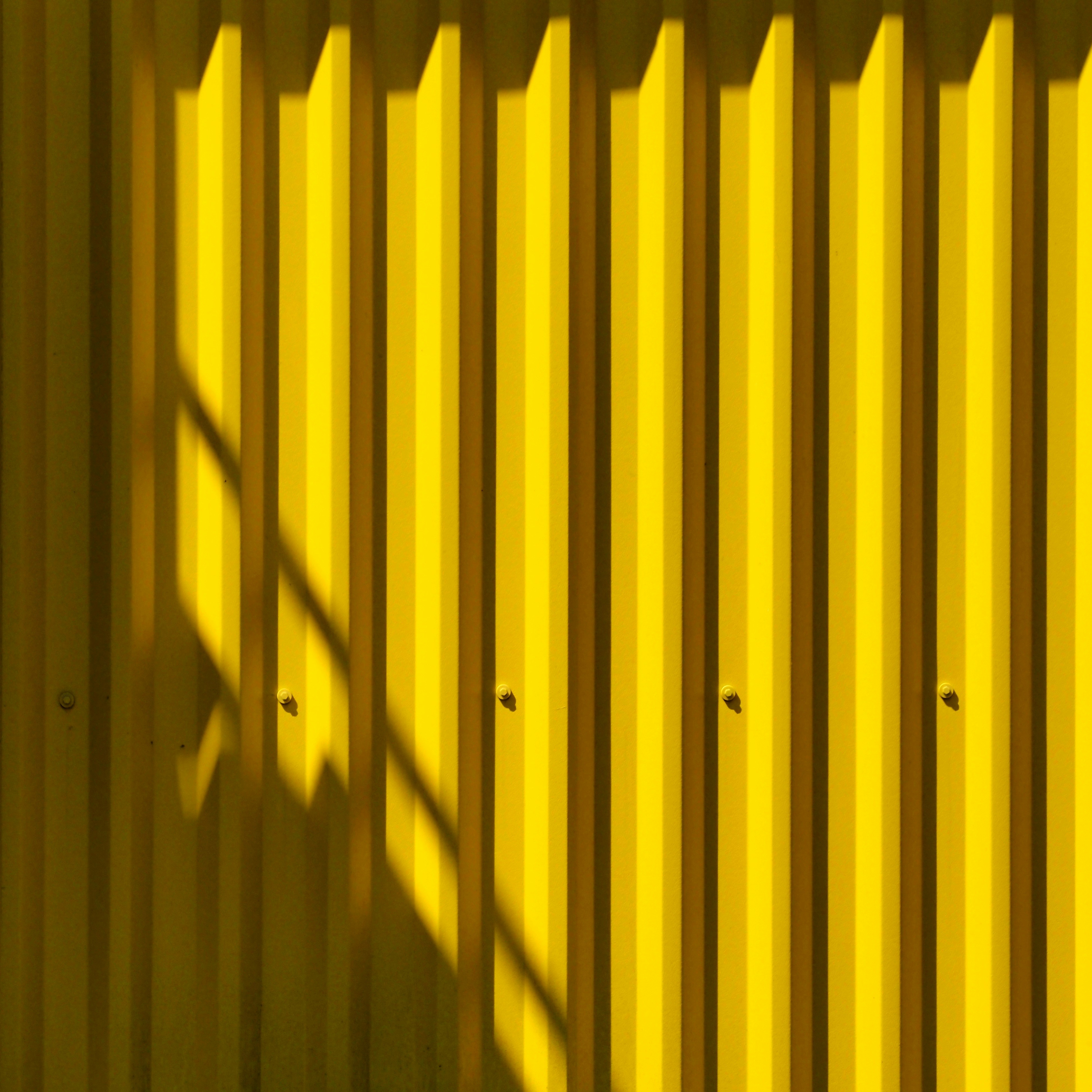 Sunlit Ridges: Shadows Crossing a Yellow Facade