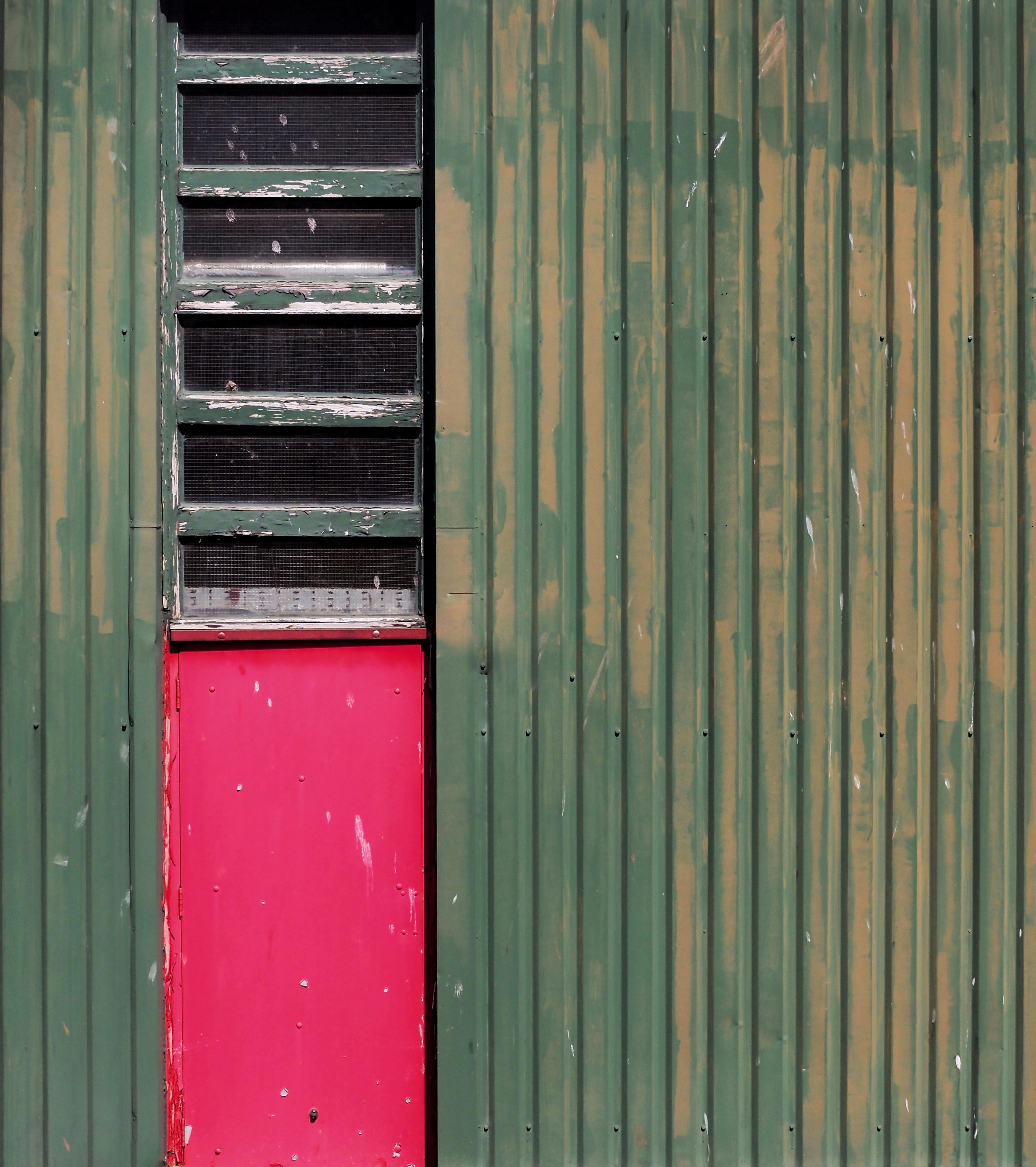 Weathered Green Metal Facade with Bright Pink Vent Dish