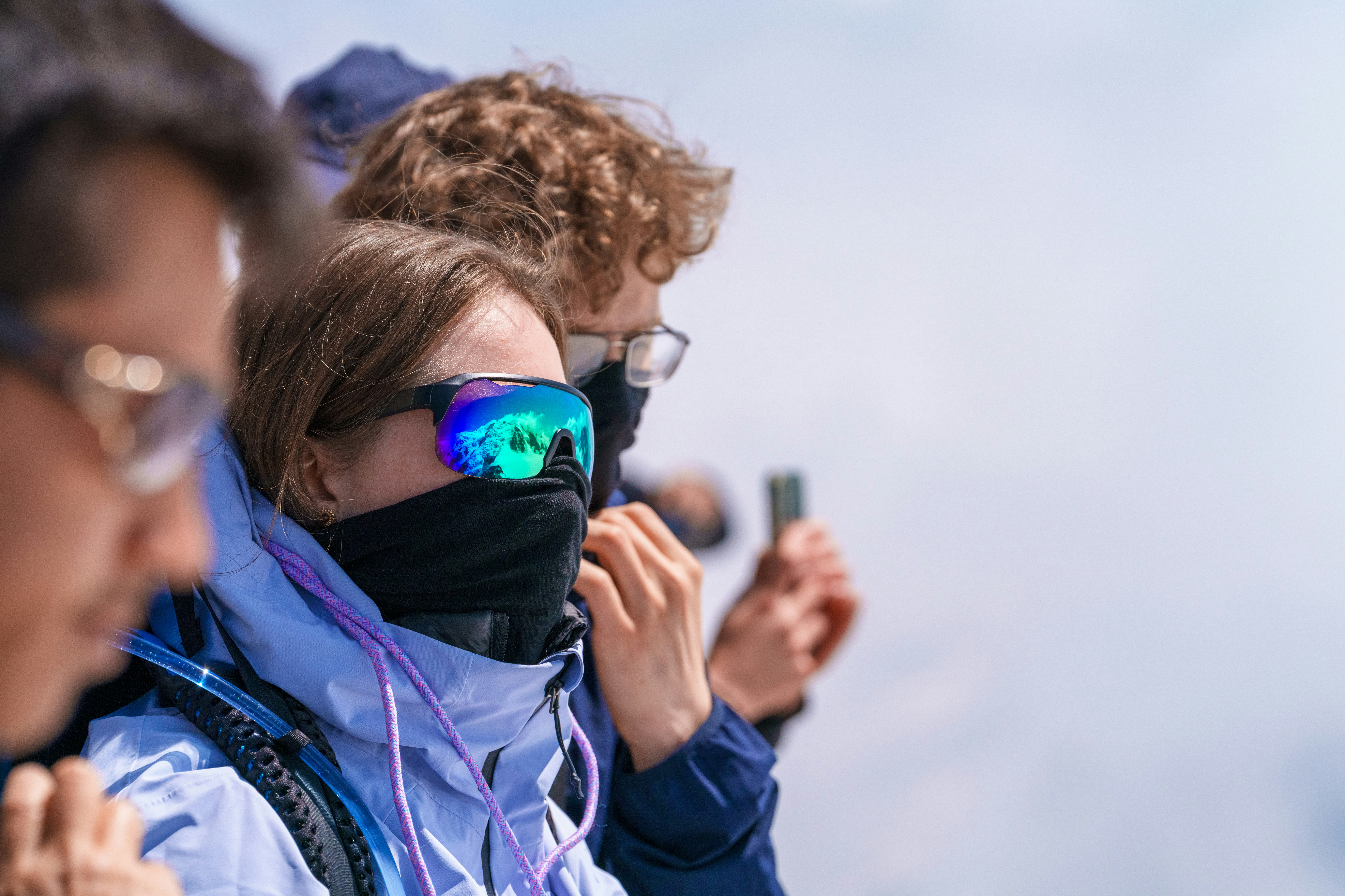 Masked observer with mirrored sunglasses amid a line-up of spectators
