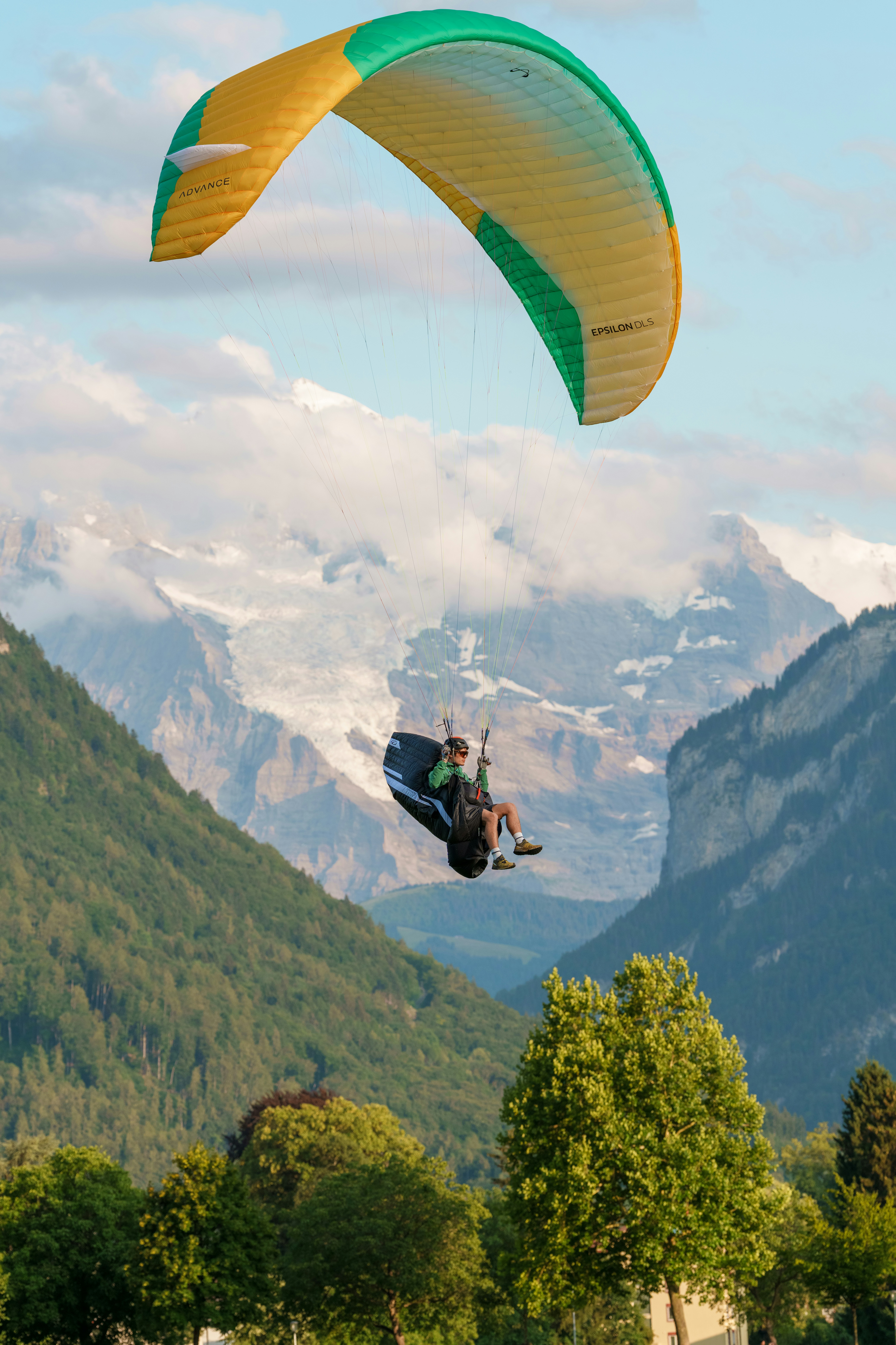 Soaring Over Alpine Valleys: A Solo Paraglider in Green and Gold