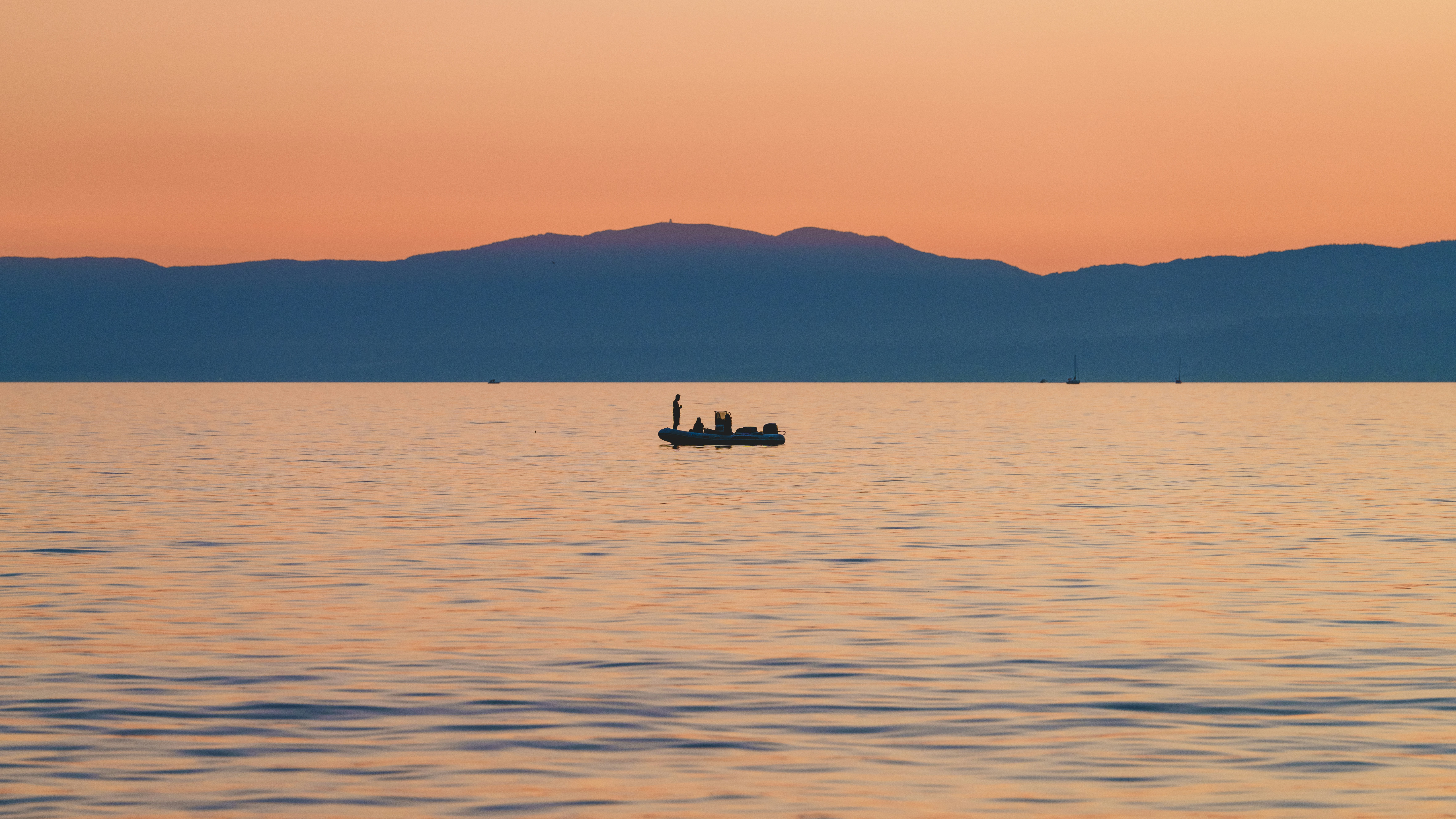 Silhouette on the Quiet Sea: Dusk over a Distant Boat