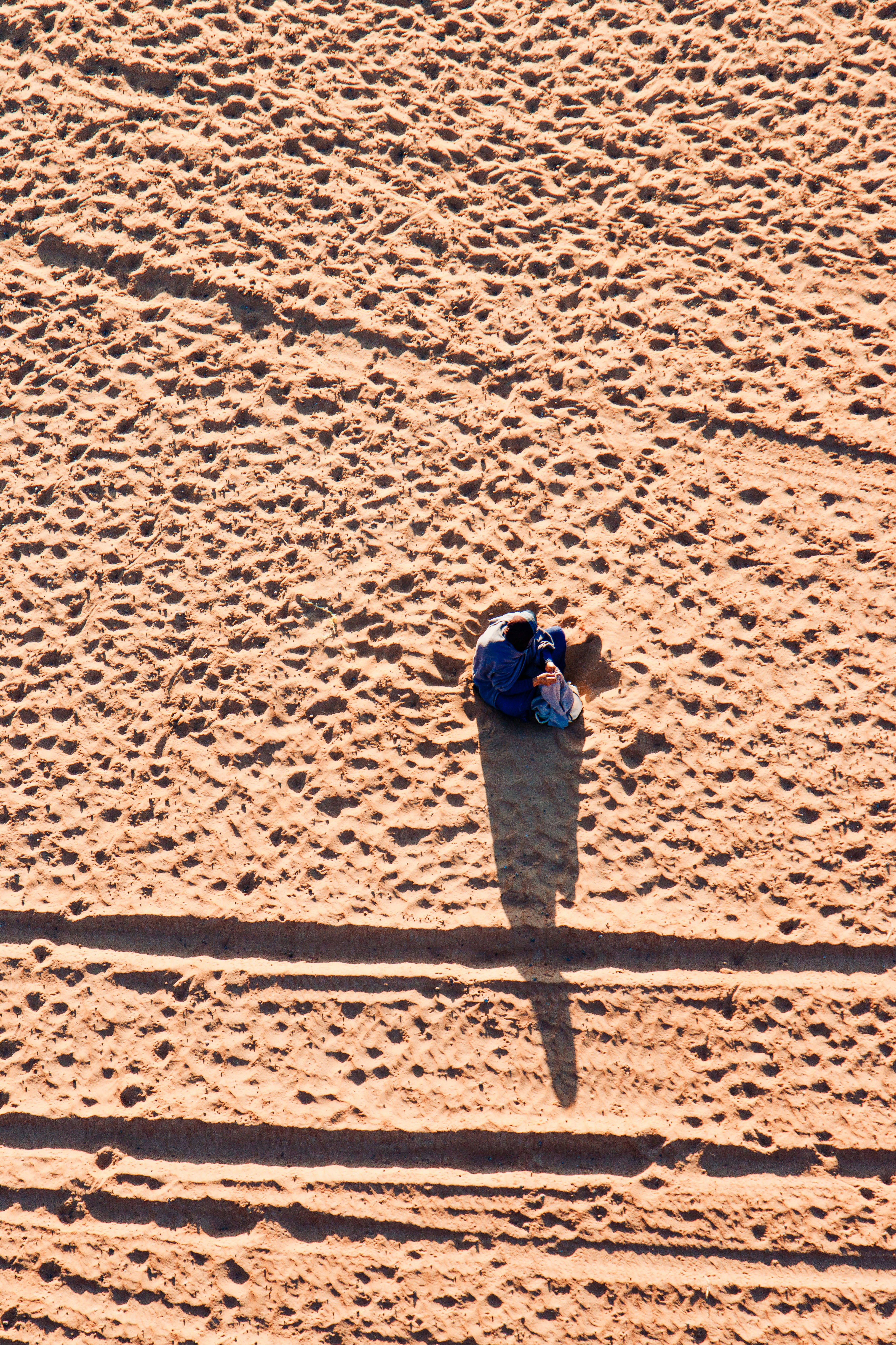 A Quiet Figure in the Sand: A Solo Portrait from Above