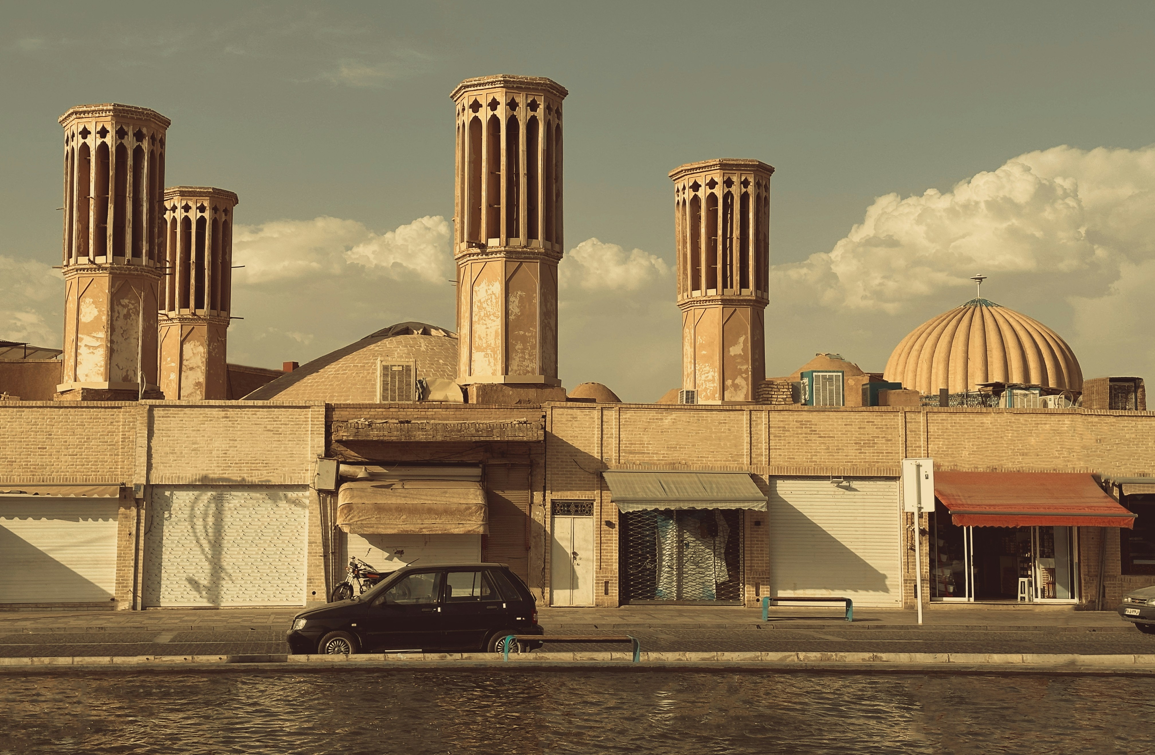 Sunlit rooftop silhouettes along a canal promenade