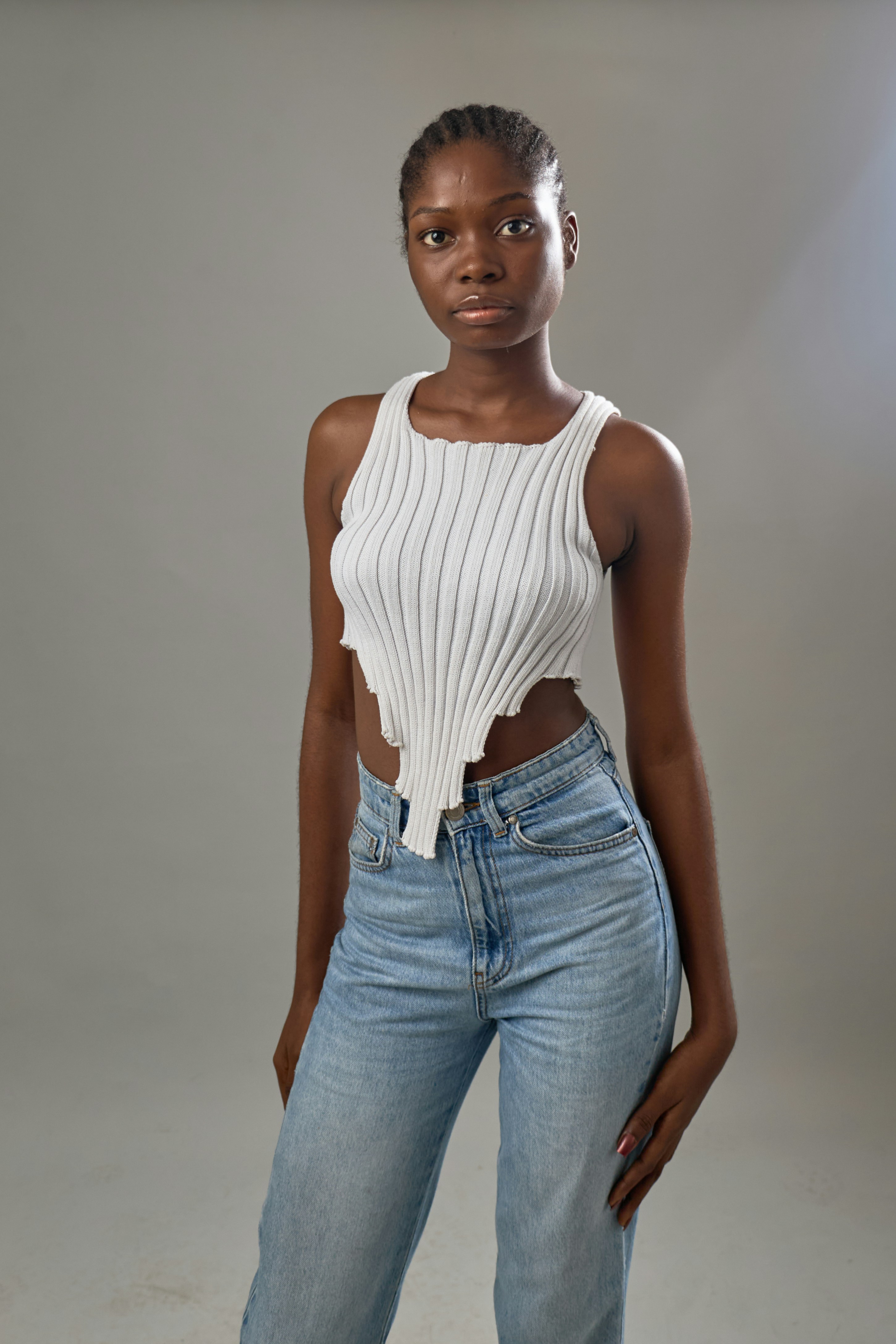 A young woman wearing a white ribbed top and jeans.