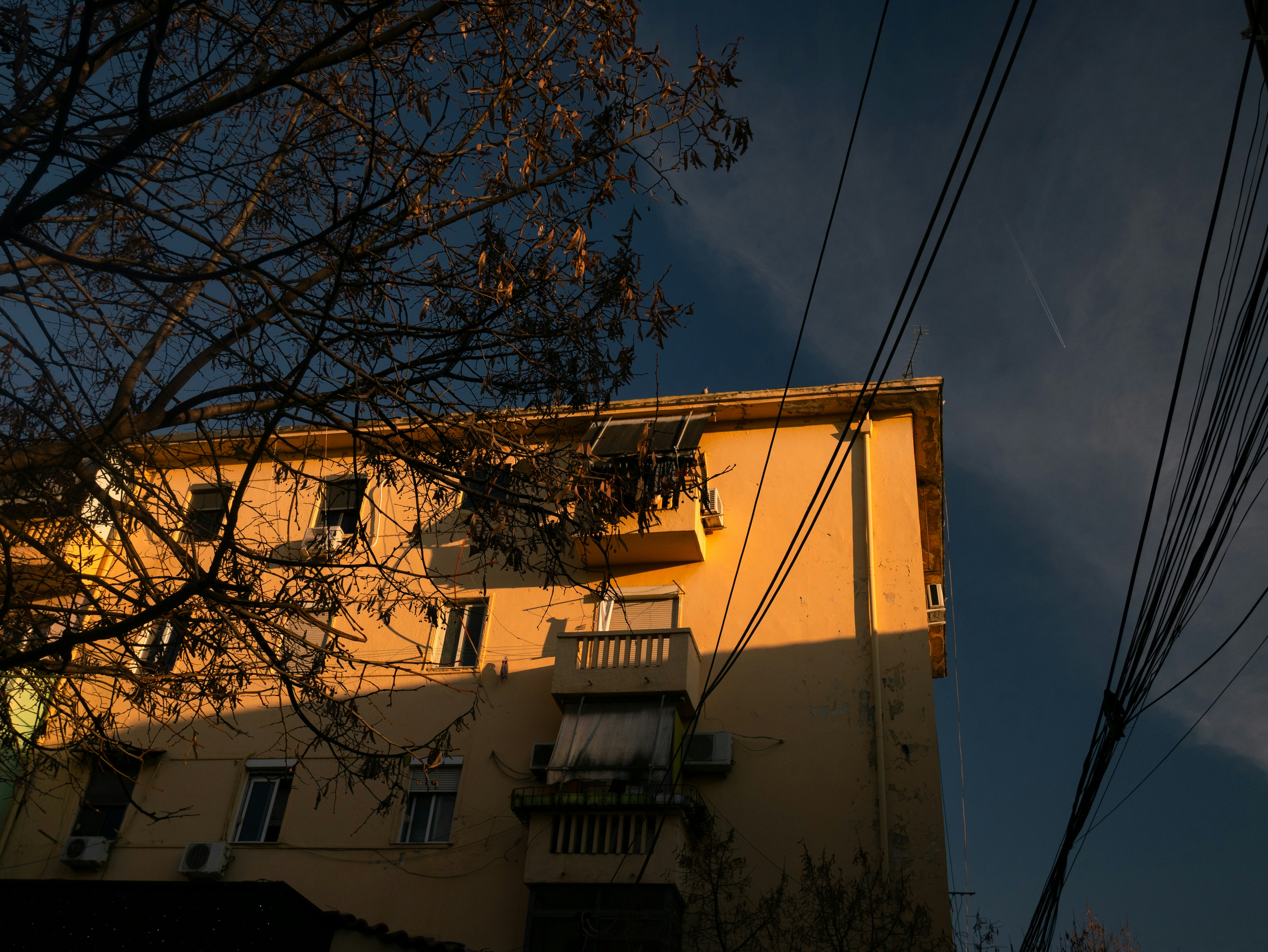 Sunlit Corner: A Yellow Apartment Block under a Clear Evening Sky