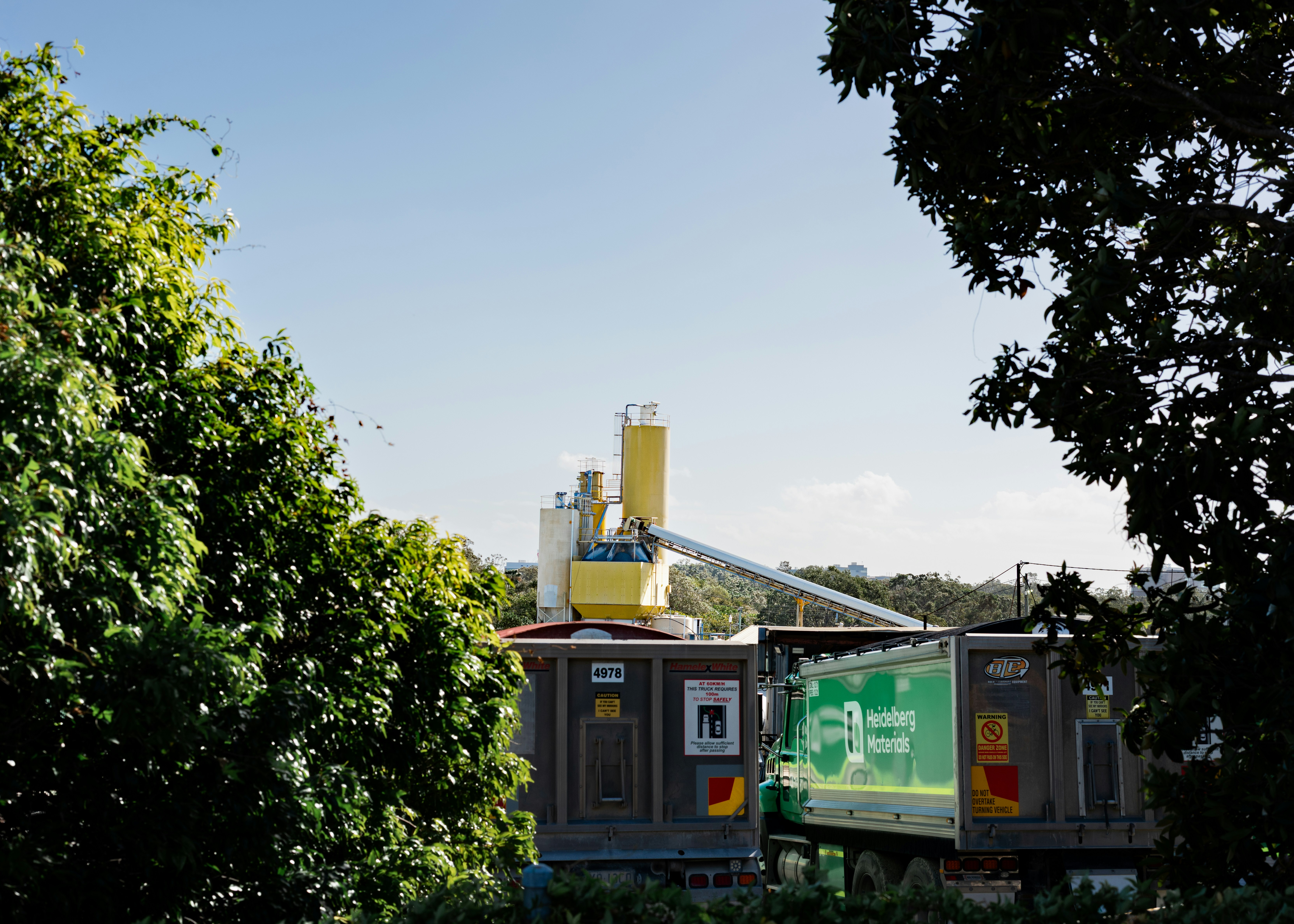Industrial Crane Silhouette Behind a Truck in a Tree-Framed Site