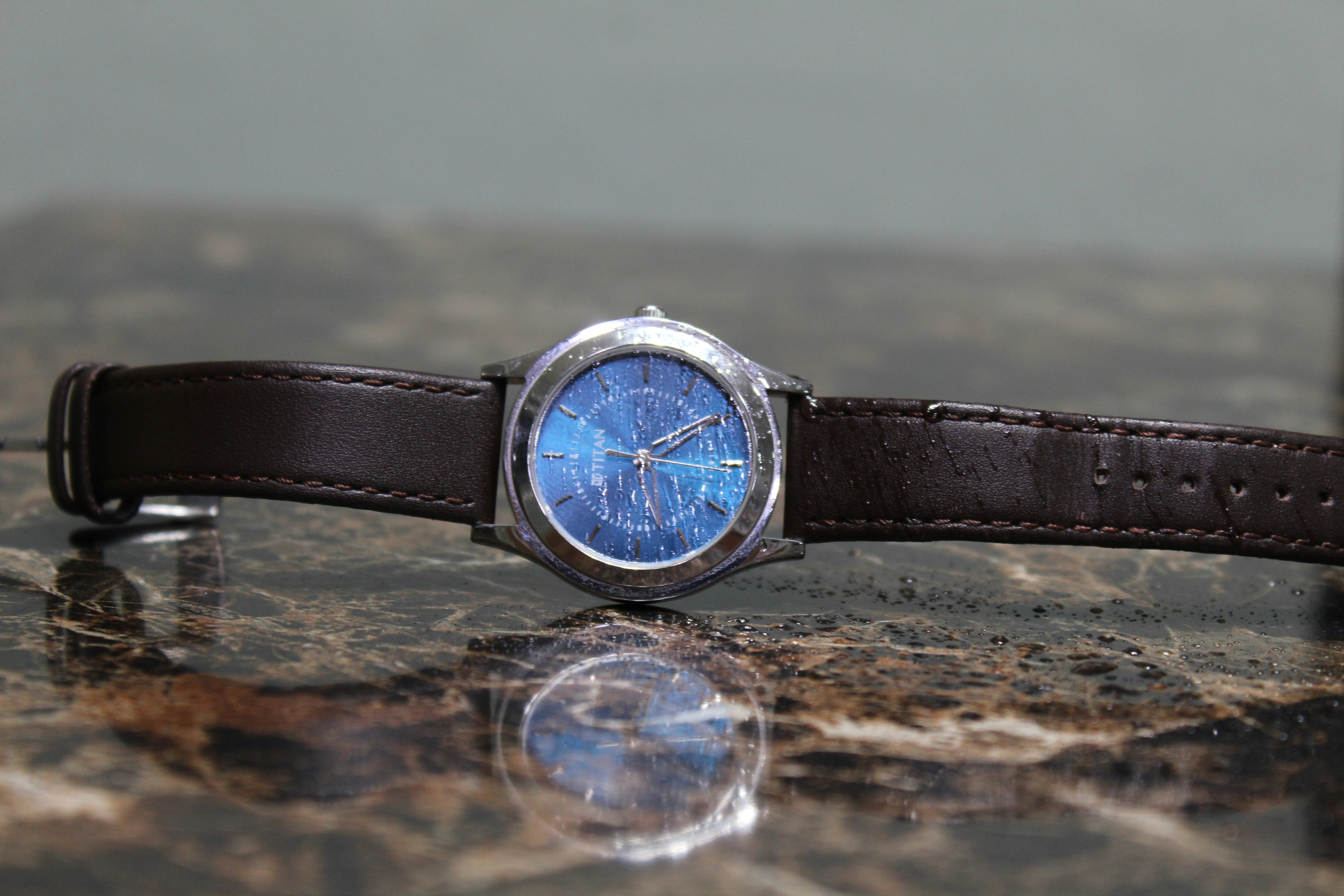 Blue-dial wristwatch resting on a polished tabletop