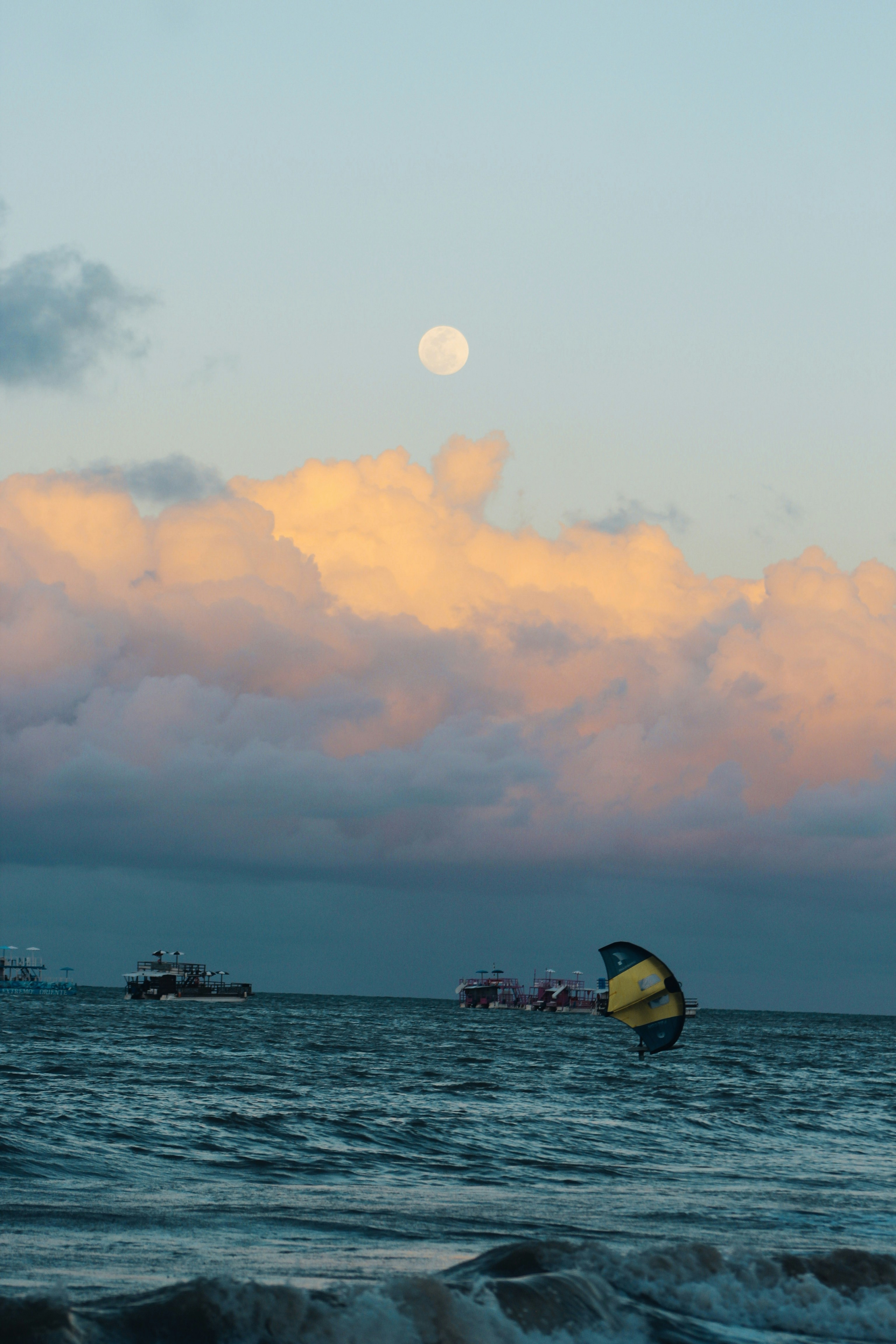 Moonrise over a calm horizon with a lone kite Surending the sunset