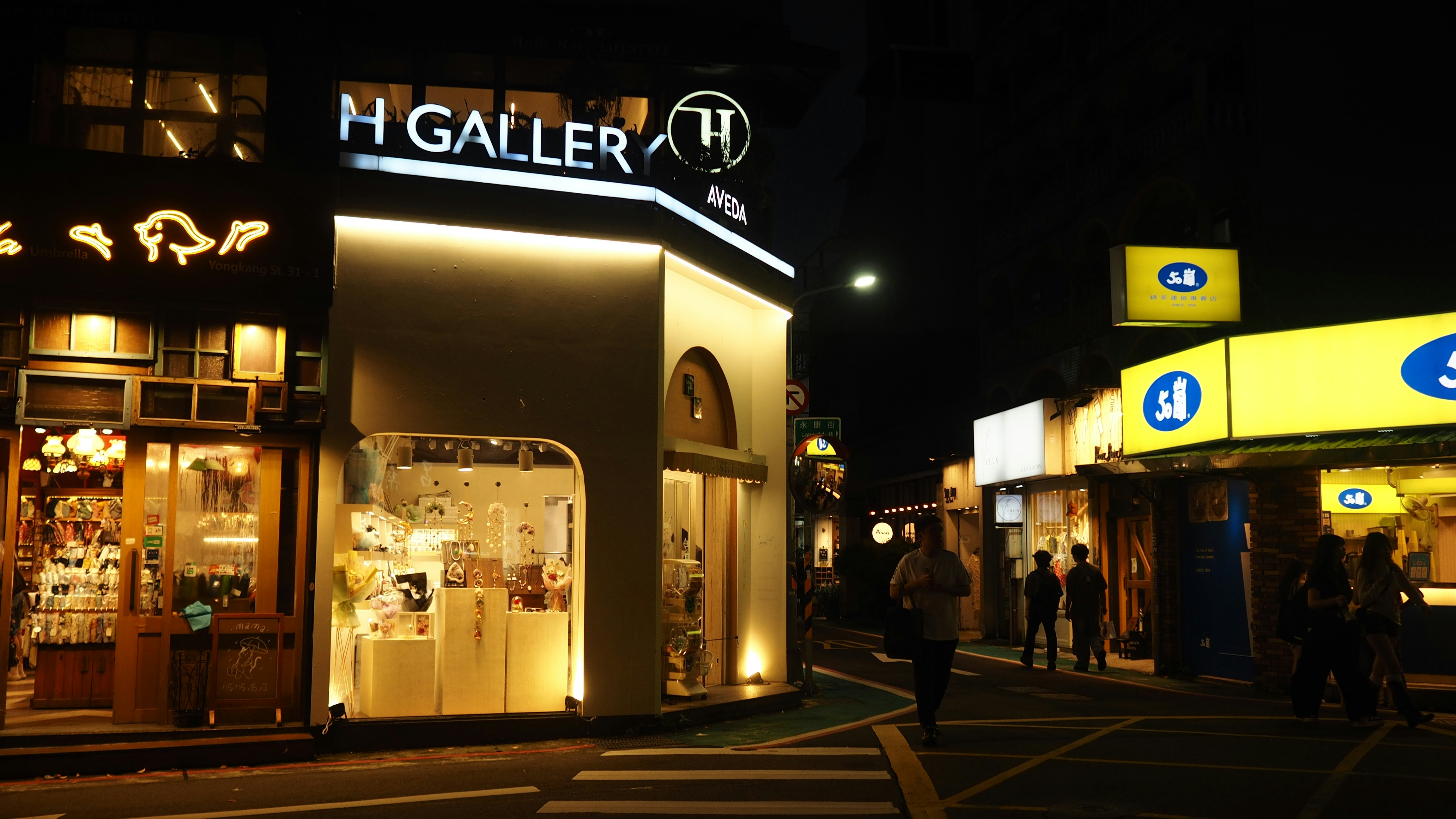 Night storefront glow: a quiet street converges on illuminated shopfronts