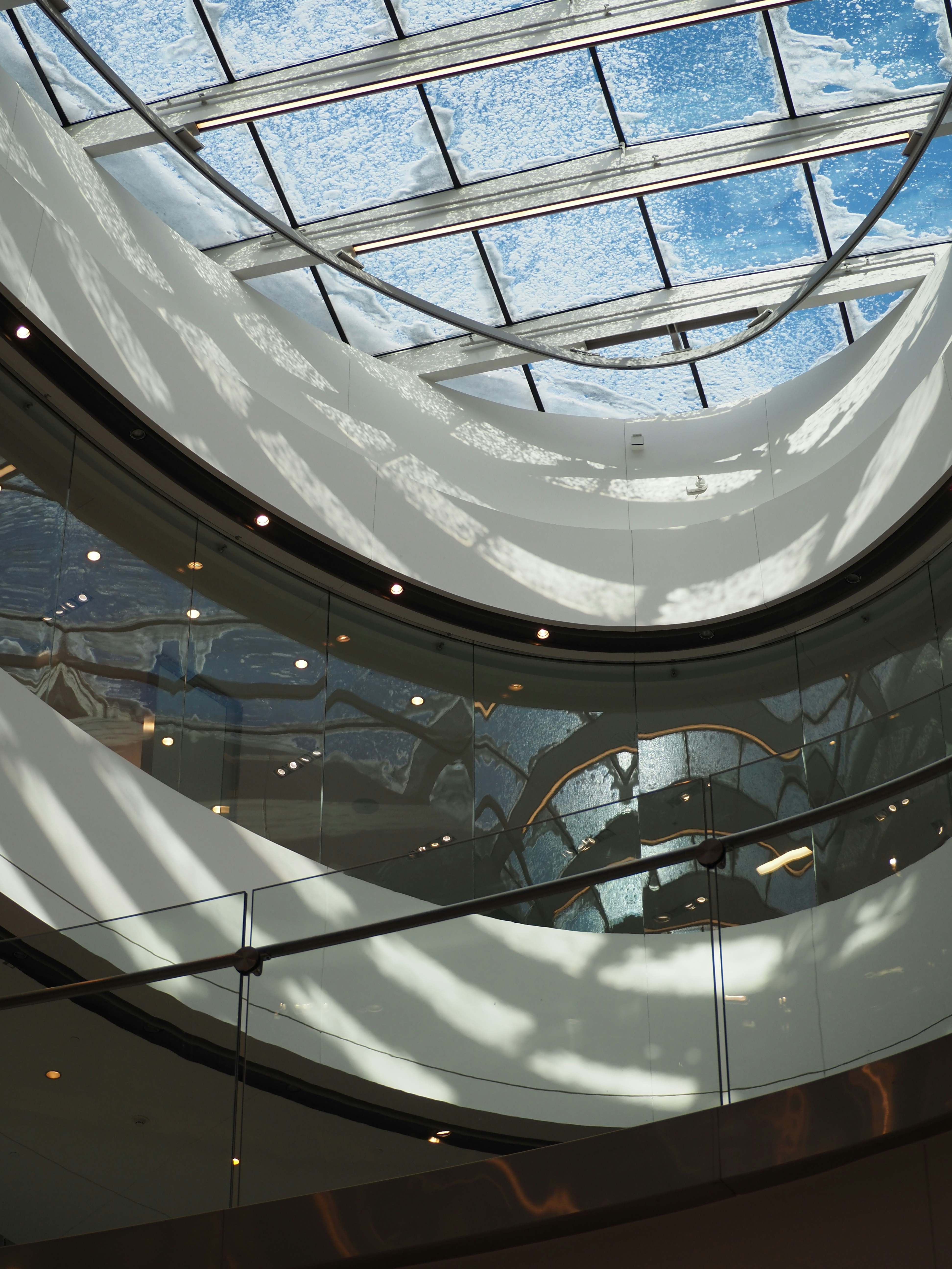 Curved Glass Atrium: Light and Shadow Play Across Spiraling Balustrade