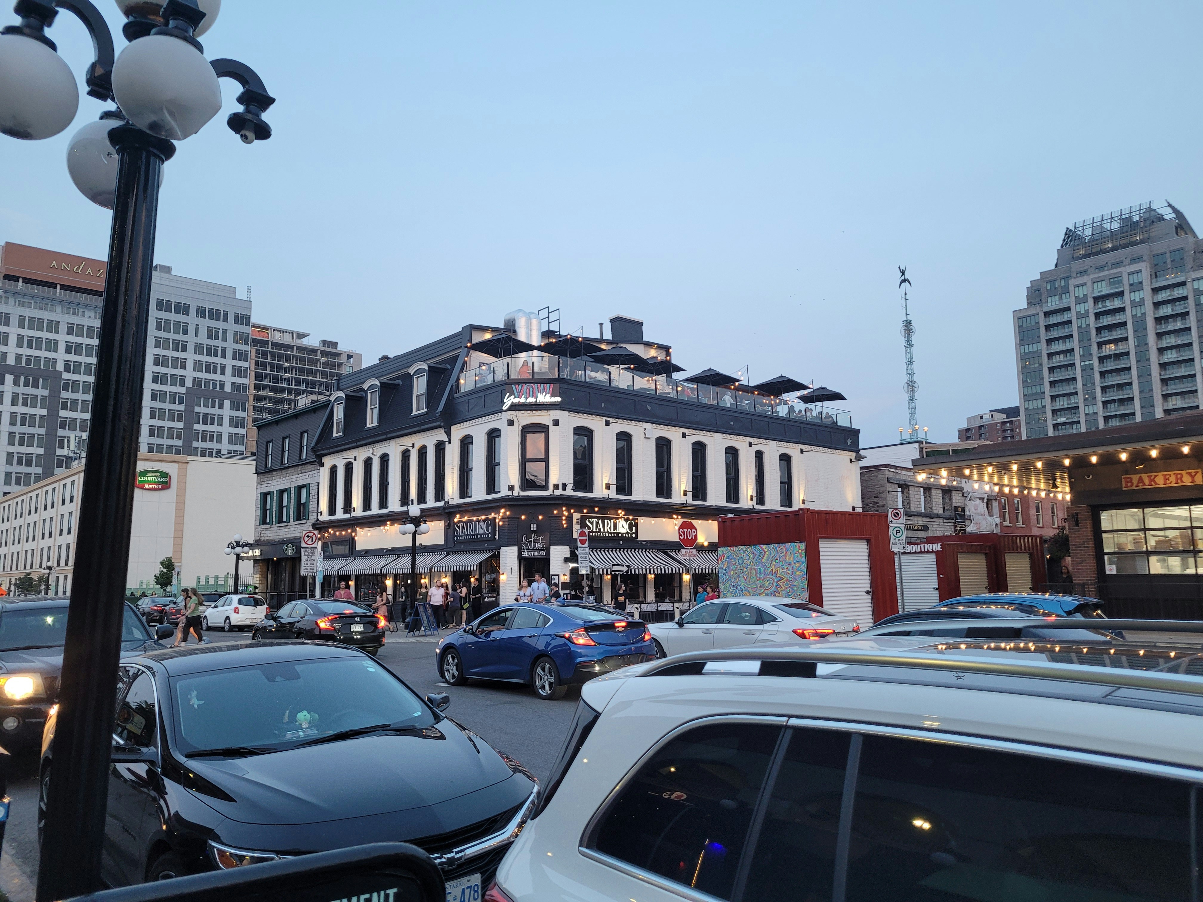 Urban Corner: A Corner Café Framed by Cars and City Silhouettes