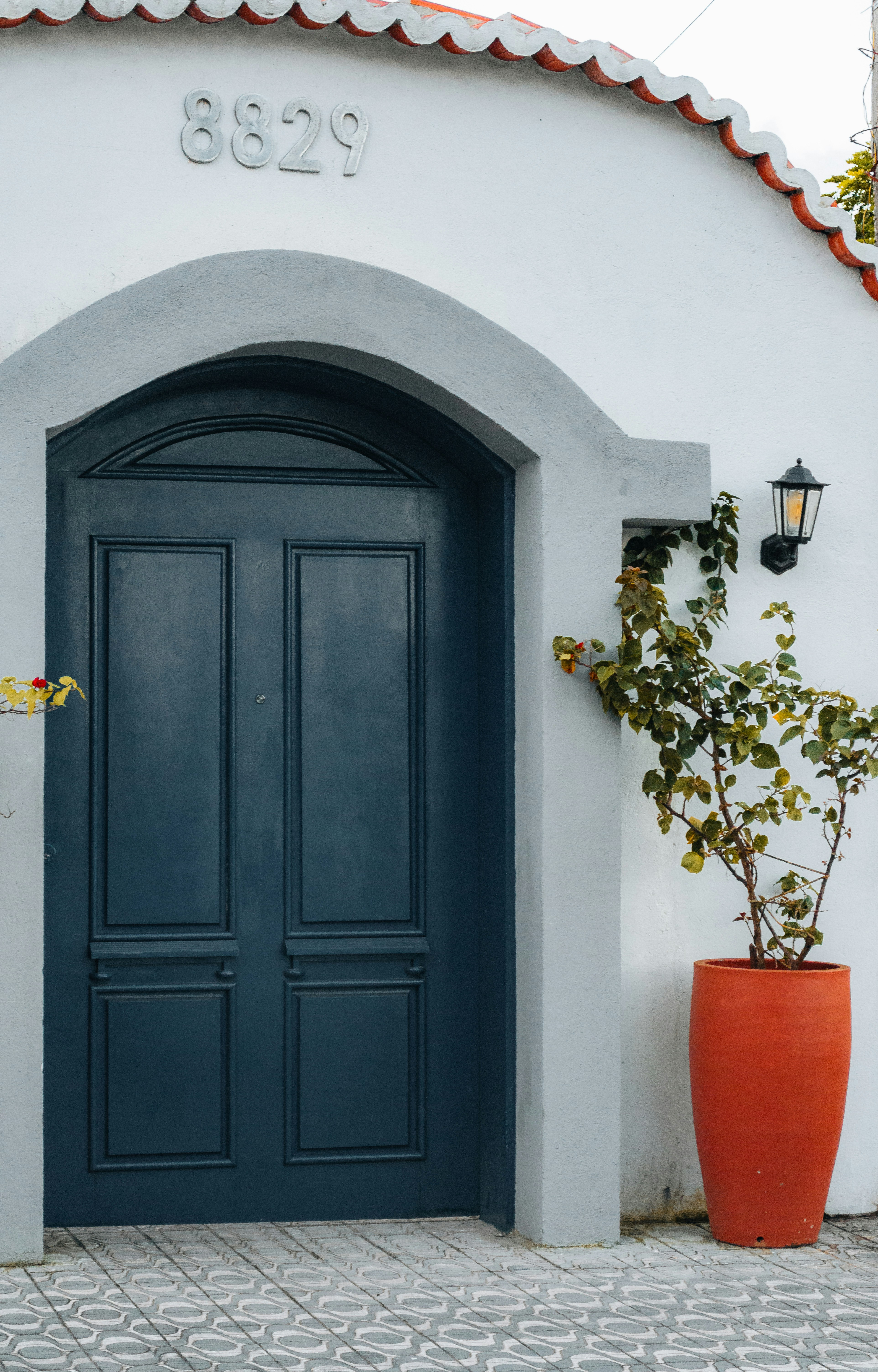 Blue door beneath a white archway framed by a terracotta pot