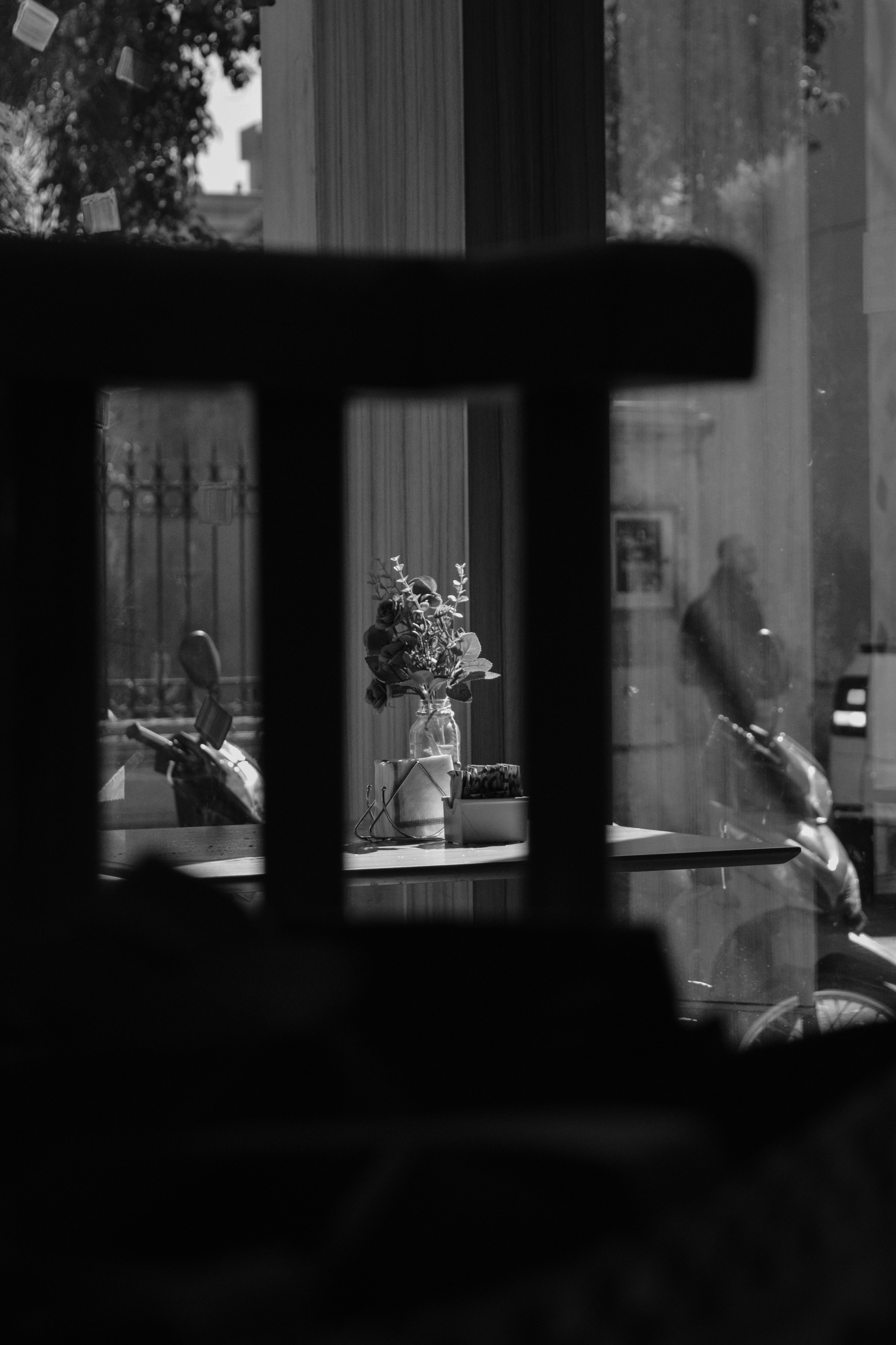 Midday Stillness: A Vase of Flowers on a Windowed Table Framed by Urban Fractions