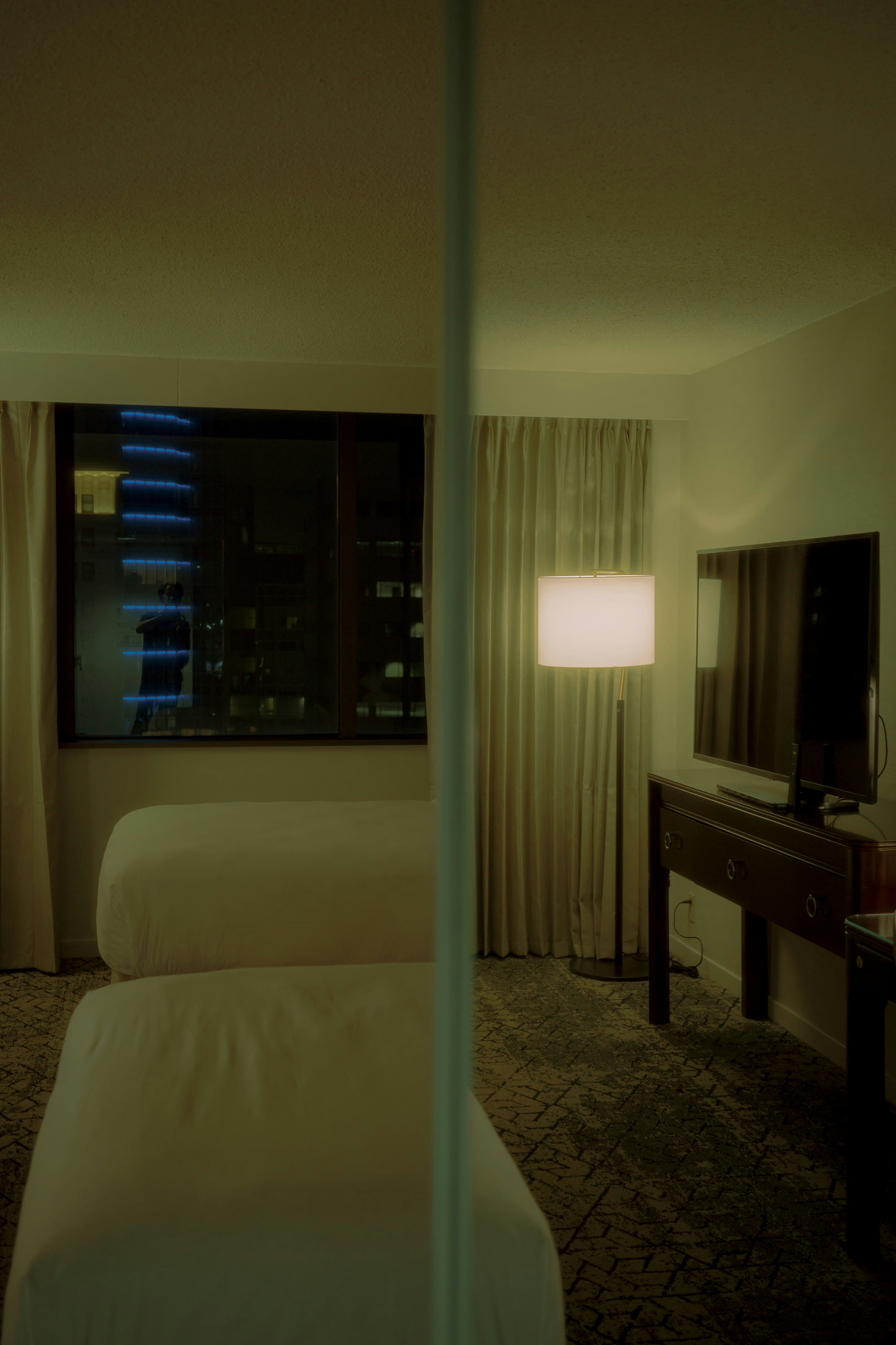 Midnight Motel Reflection: A Dimly Lit Hotel Room Through Glass and Glass Pane