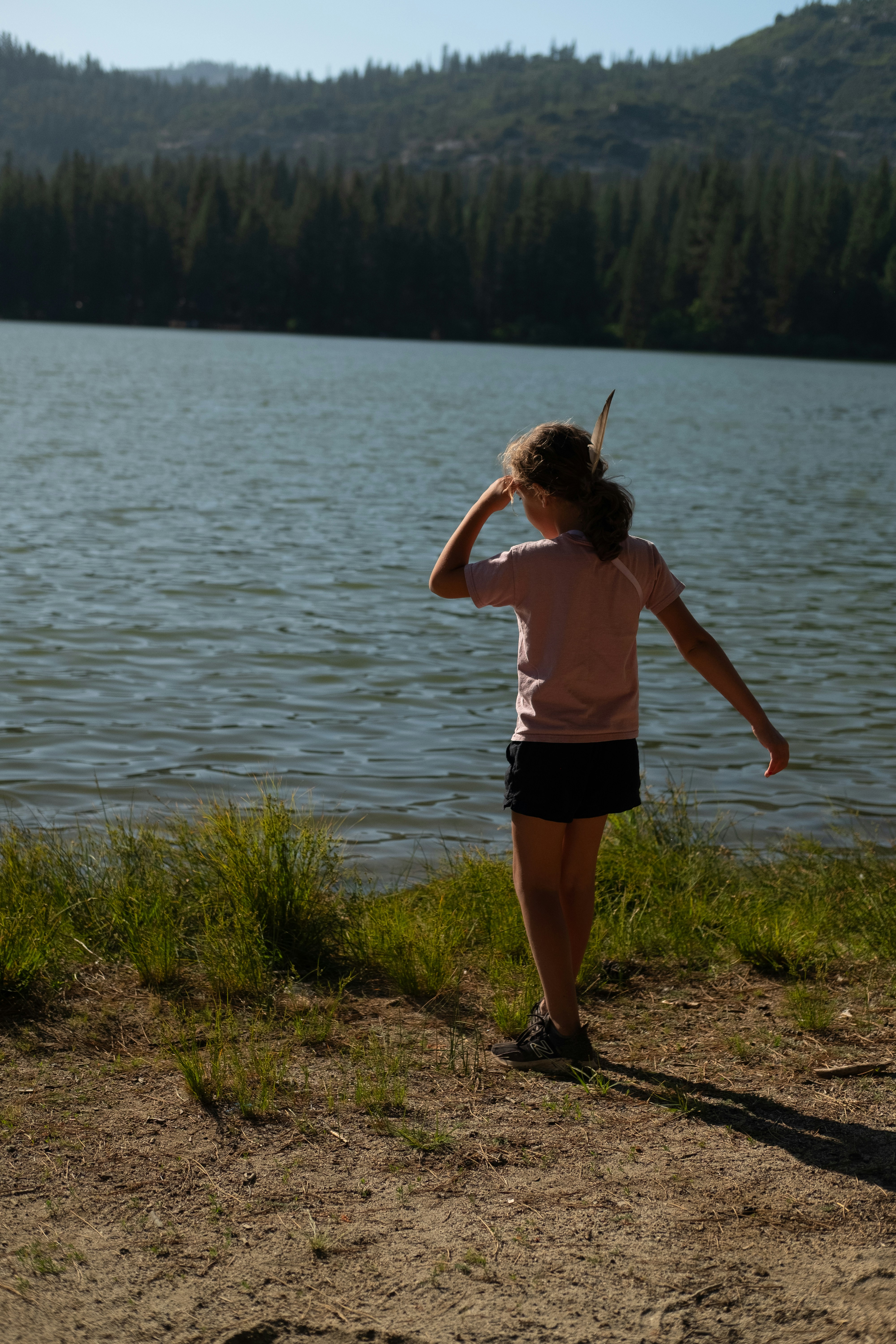 Girl by the Lakeshore: A Sunlit Moment of Playful Gaze