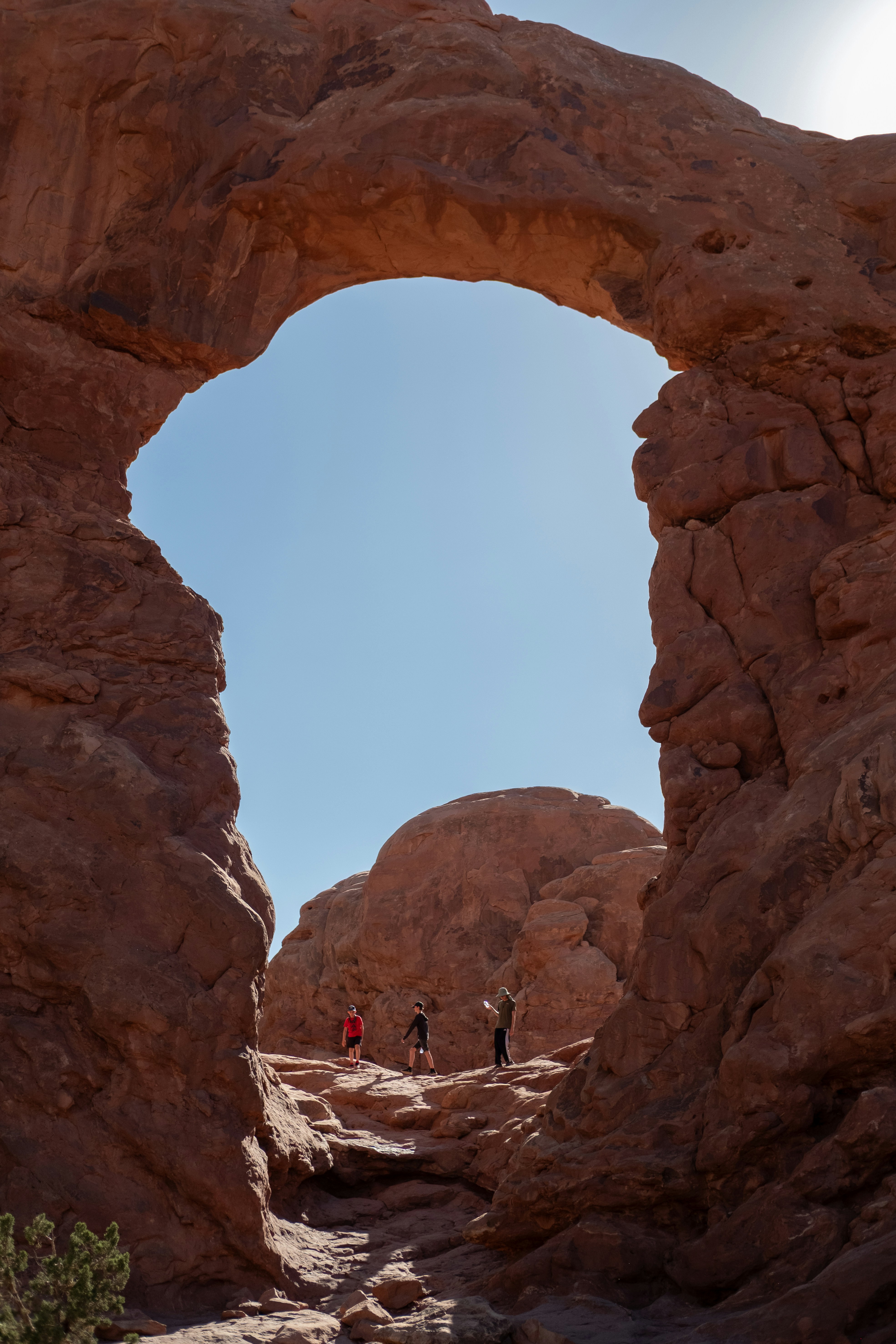 Arch of Red Rock: Explorers Beneath a Sky-Blue Window