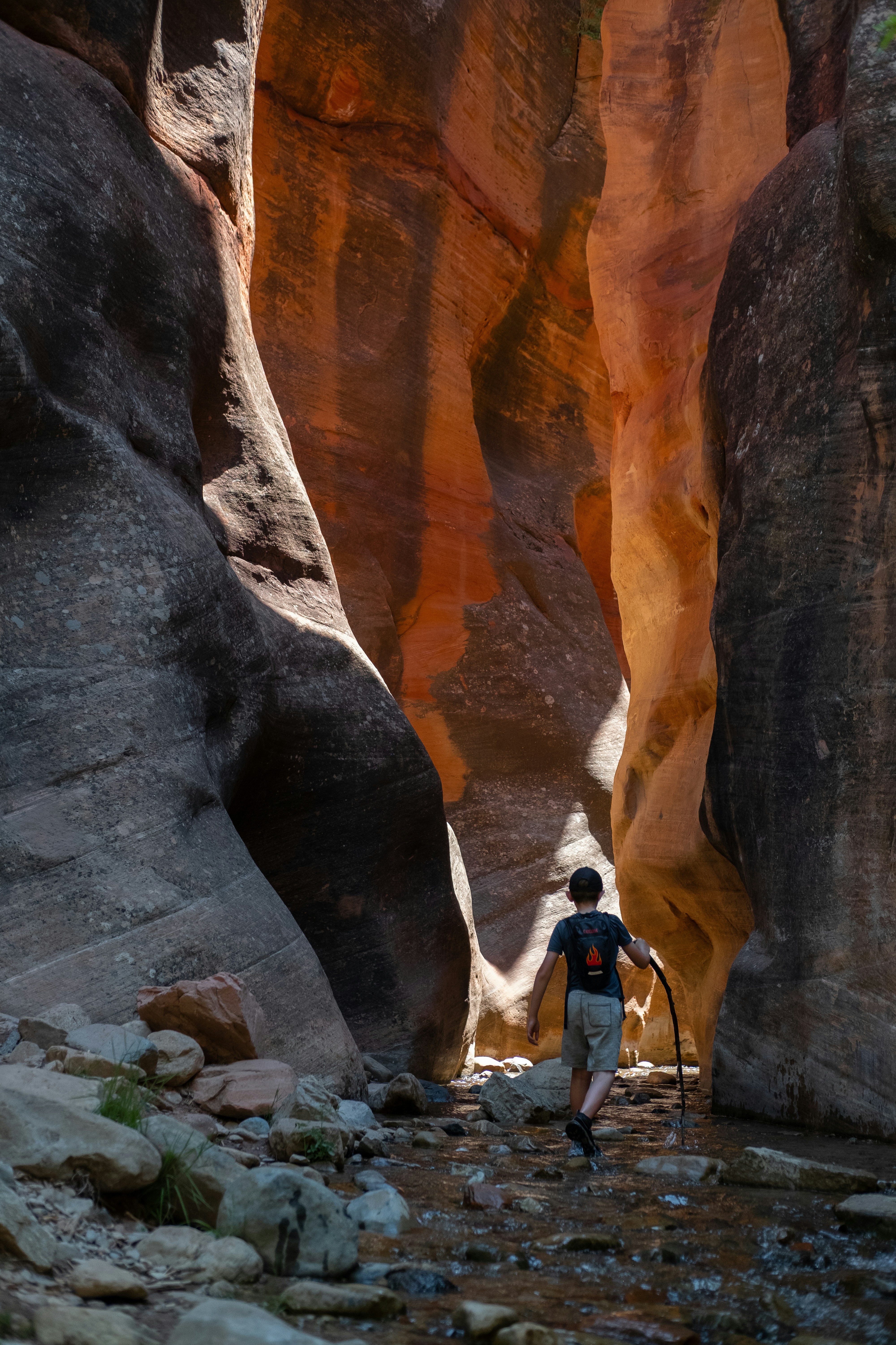 Narrow Canyon Trek: A Lone Hiker Between Sunlit Walls