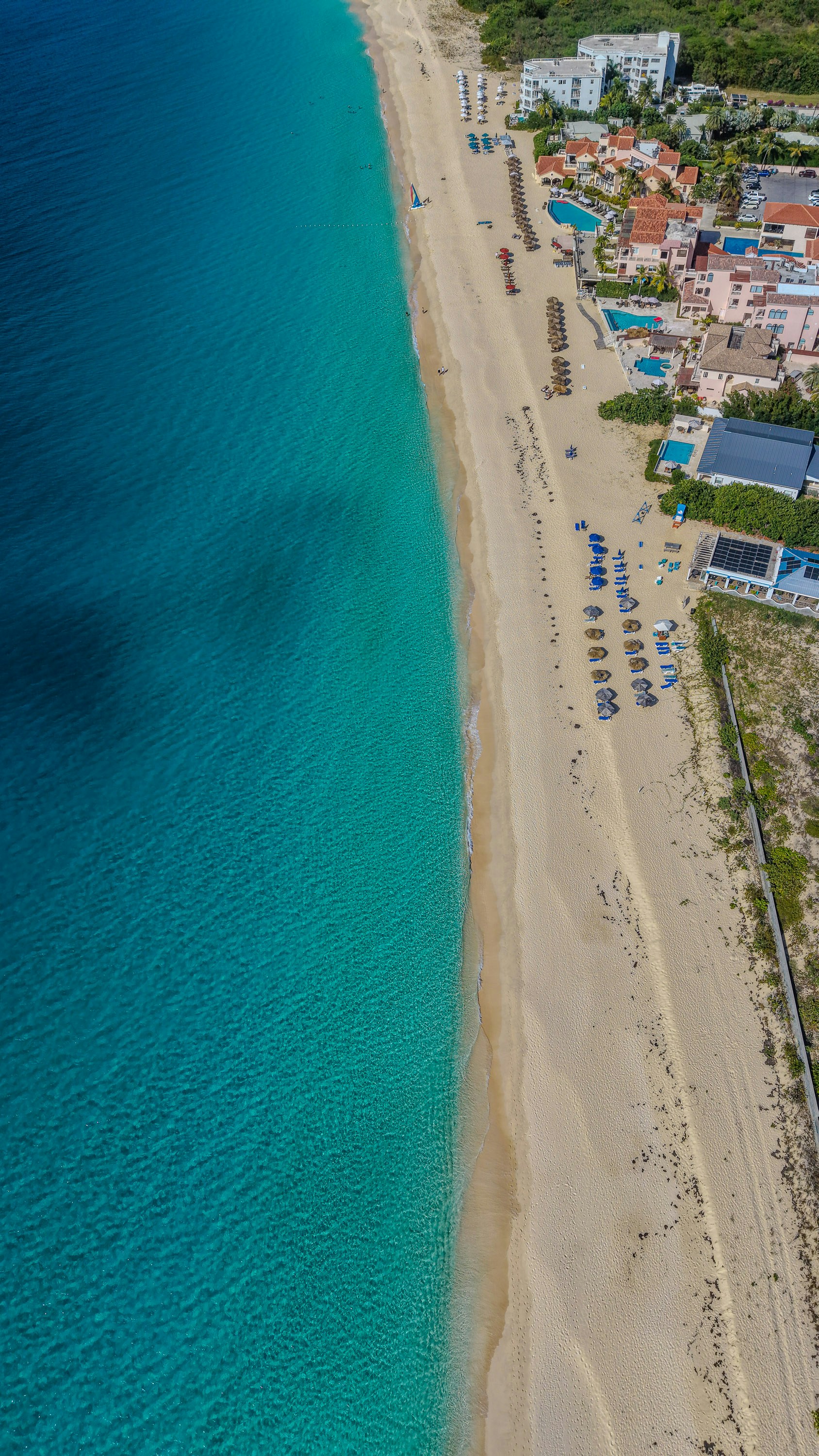 Aerial Strip: Turquoise Sea Meets Sunlit Beachfront Village