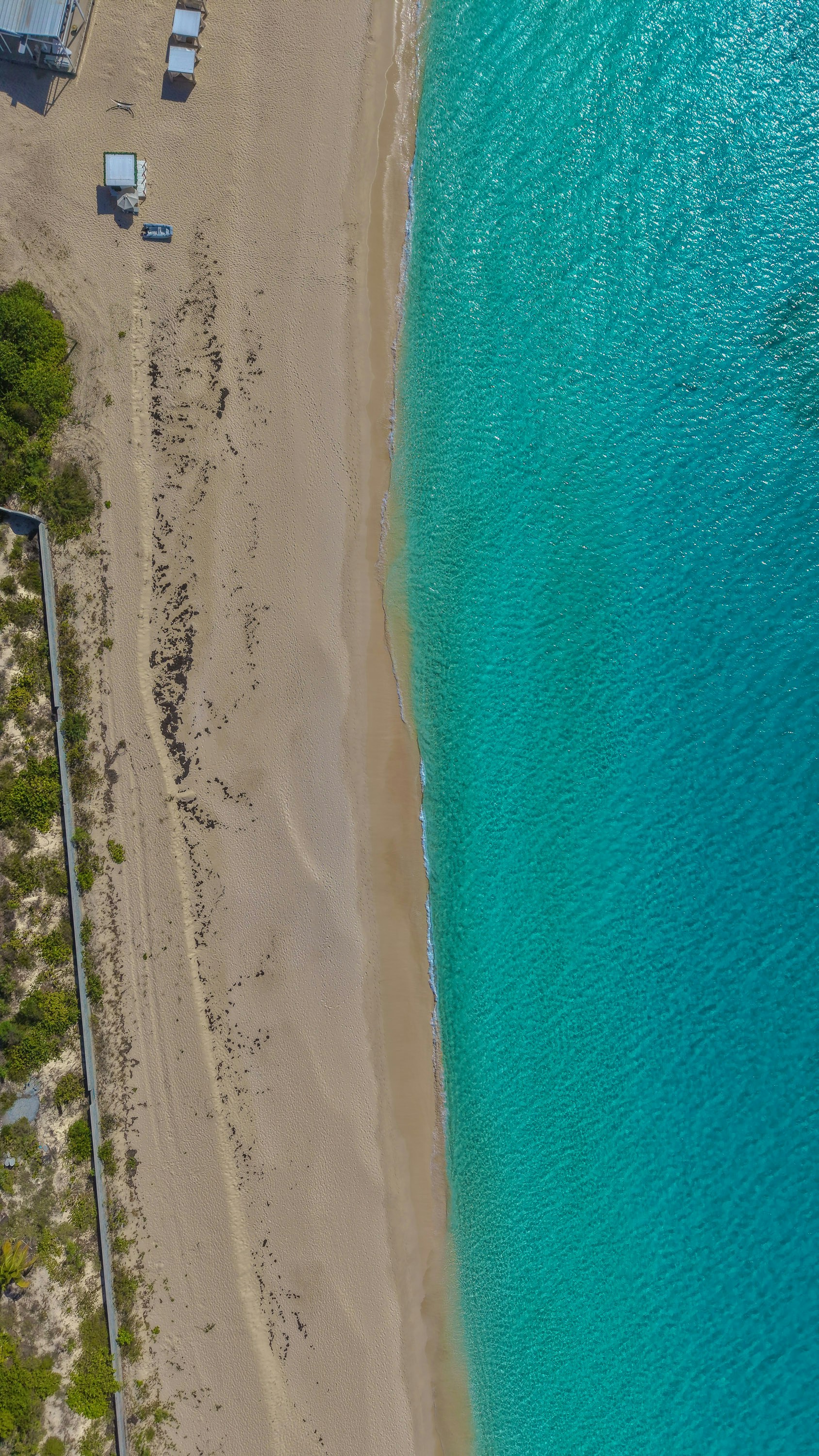 Aerial shoreline: turquoise sea meeting a quiet, sunlit beach
