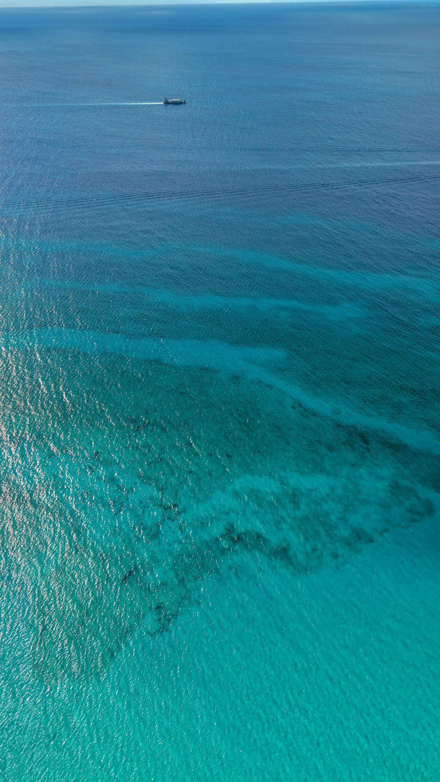 Azure Gradient: A Lone Vessel Cruising the Sea’s Lacelike Surface