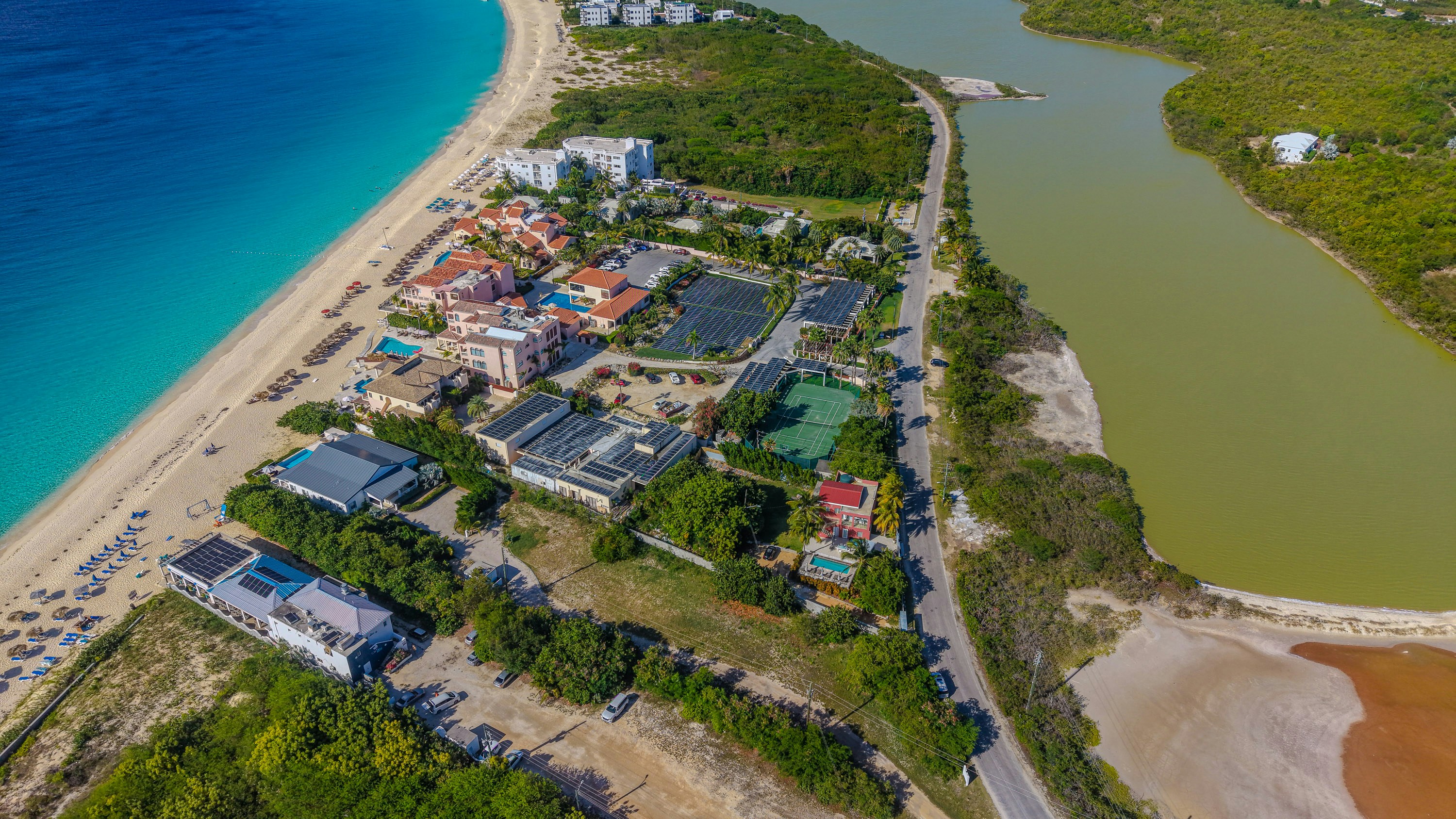 Aerial View of a Beachfront Resort Cluster Fringed by Green Wetlands