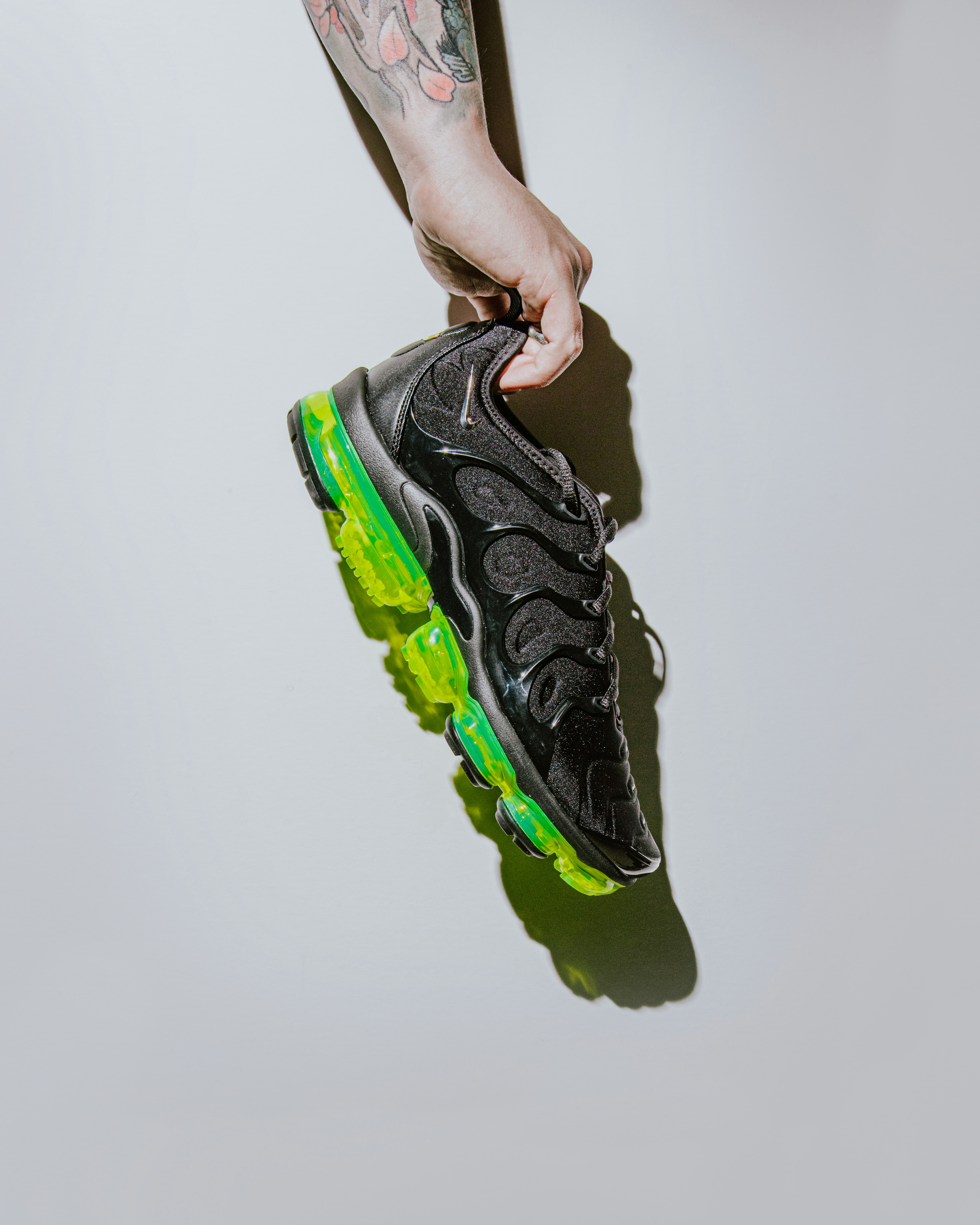 Lift Off: Neon-Soled Sneaker Gripped by a Tattooed Hand