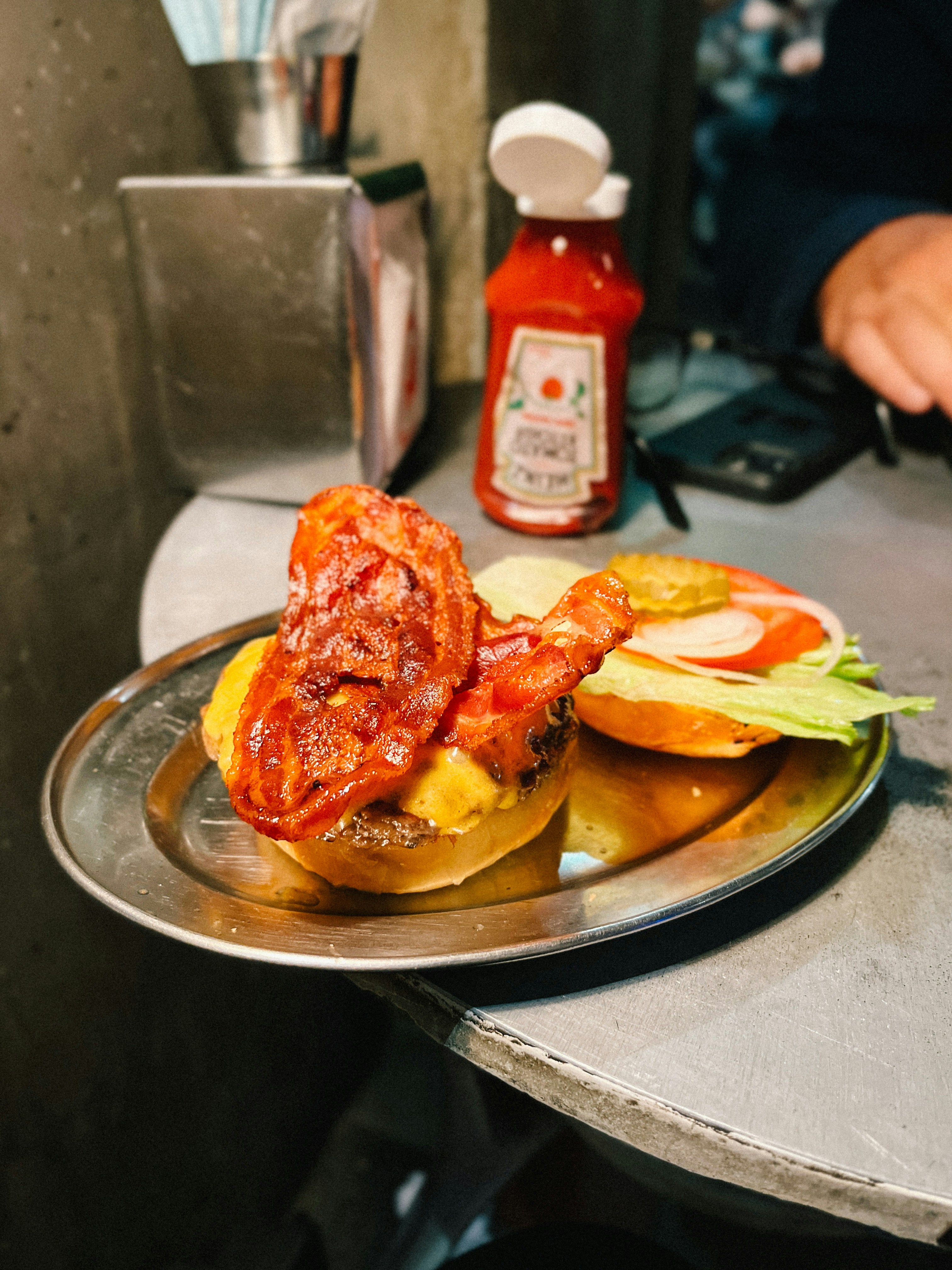 Charred bacon crown on a saucy burger amid a diner counter scene