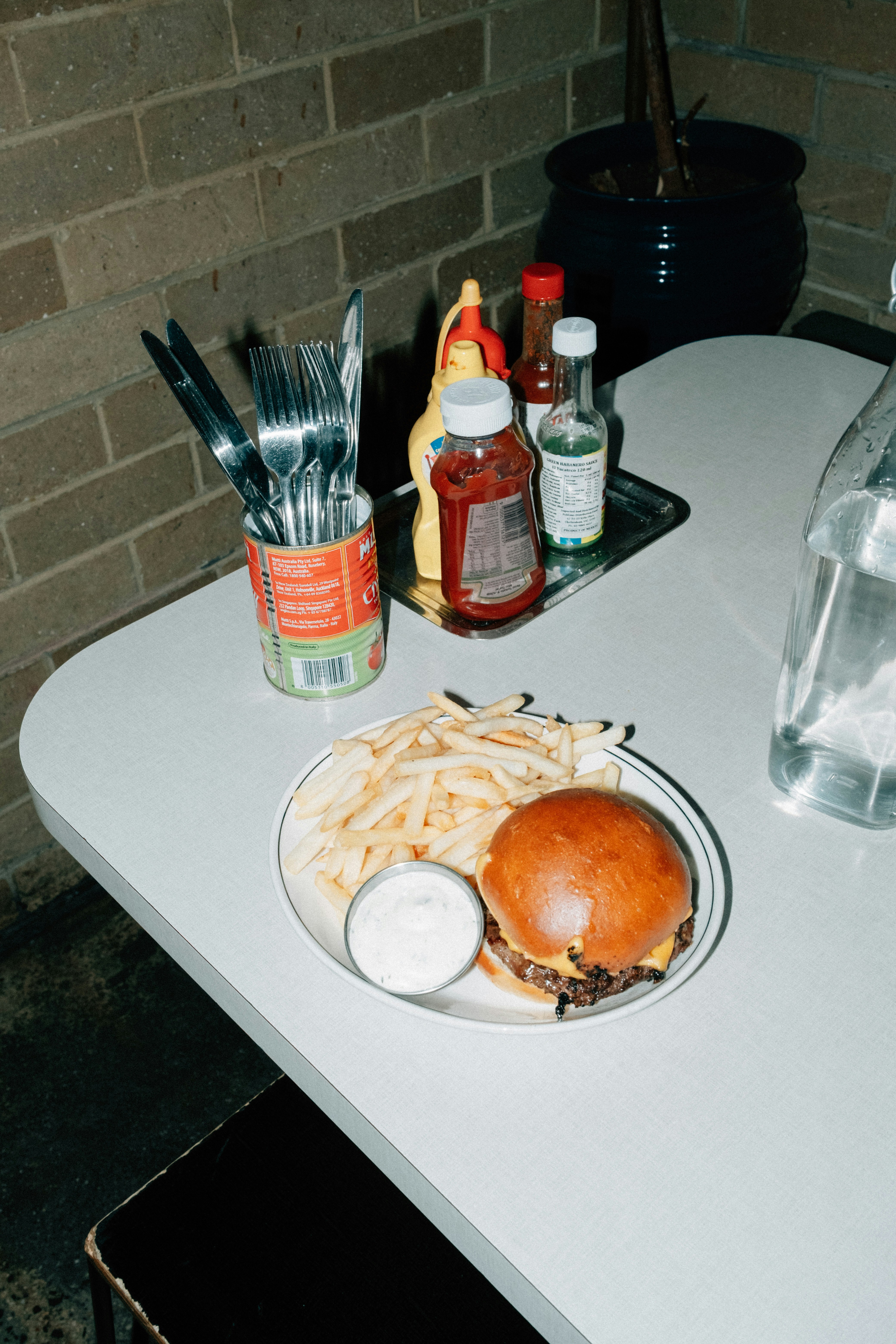 Casual Outdoor Snack Break: Burger, Fries, and Condiments on a White Table
