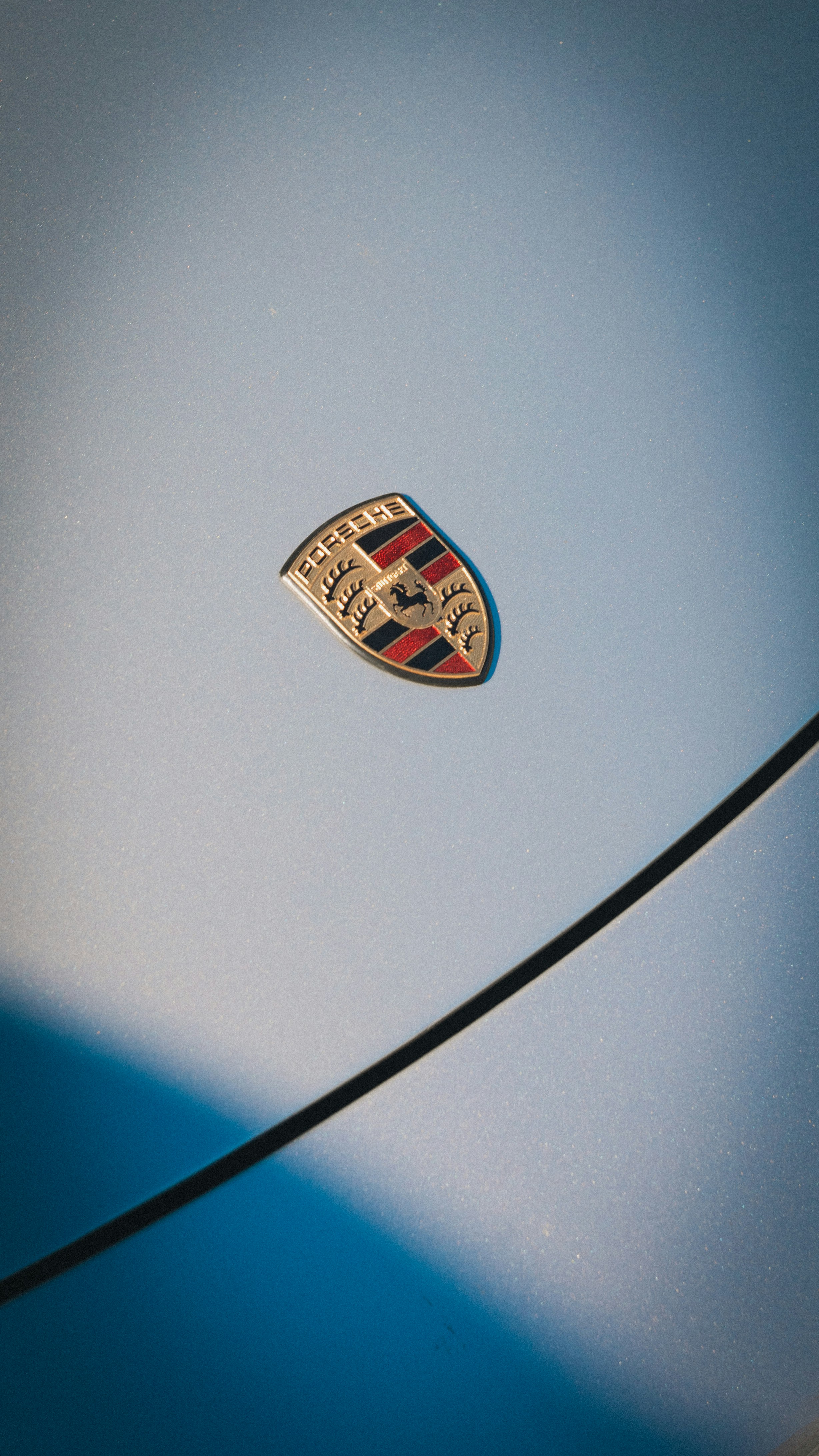 Emblem in a Blue Arc: Porsche Crest Against Night Sky