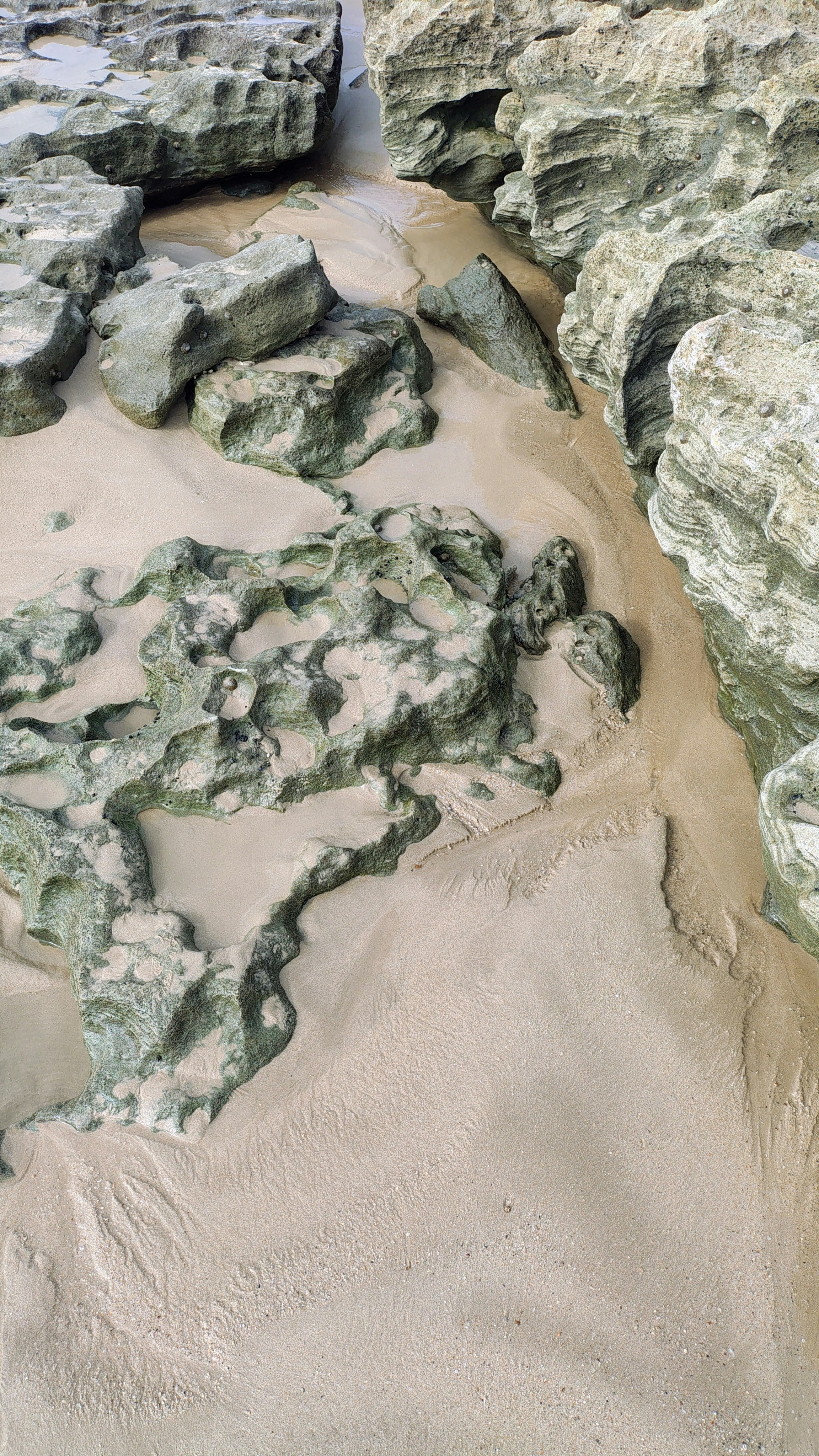 Tide-Worn Passages: Light Sand Between Weathered Rocks