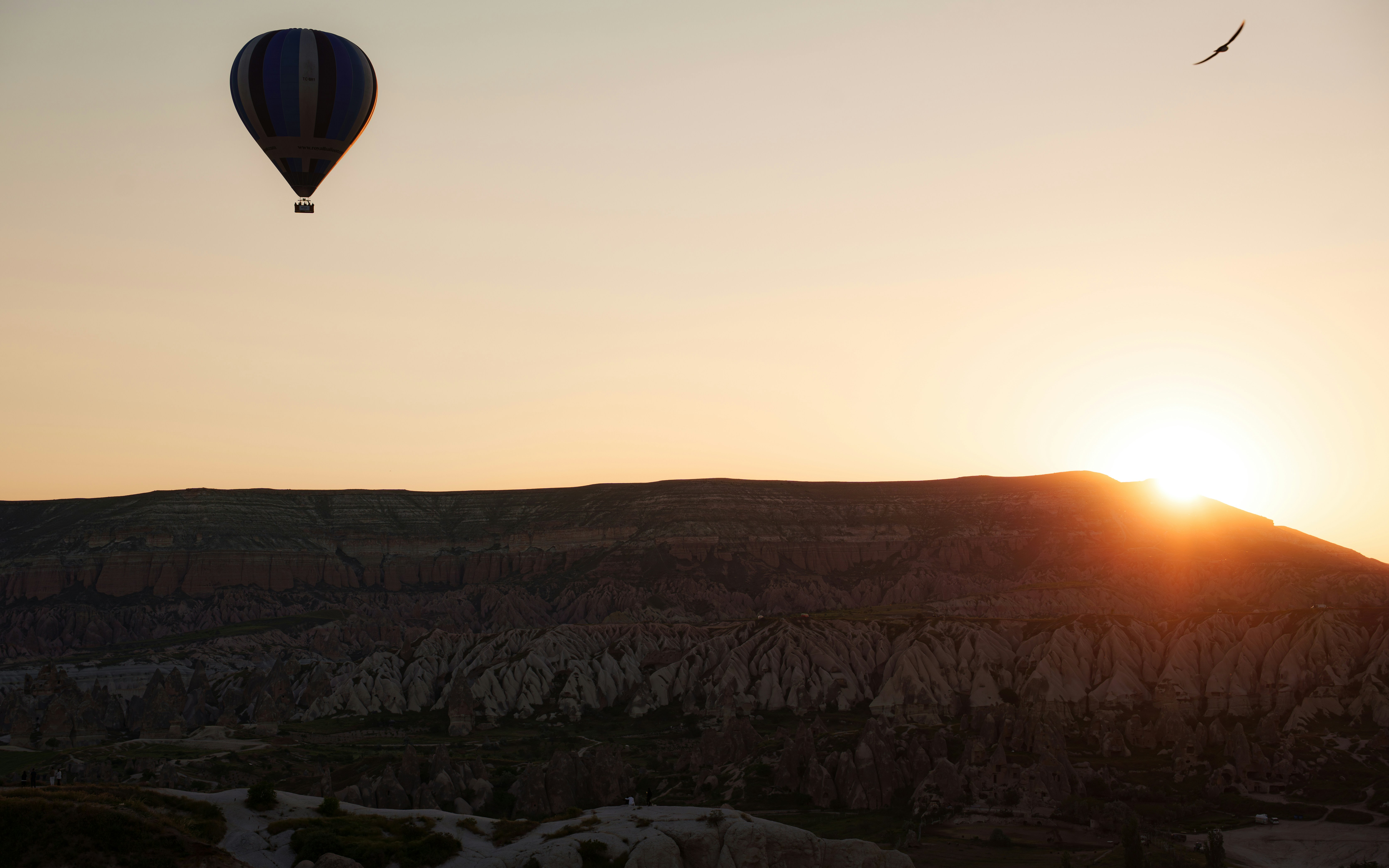 Sunlit Horizon: A Balloon Drifts Over a Desert Plateau at Sunrise