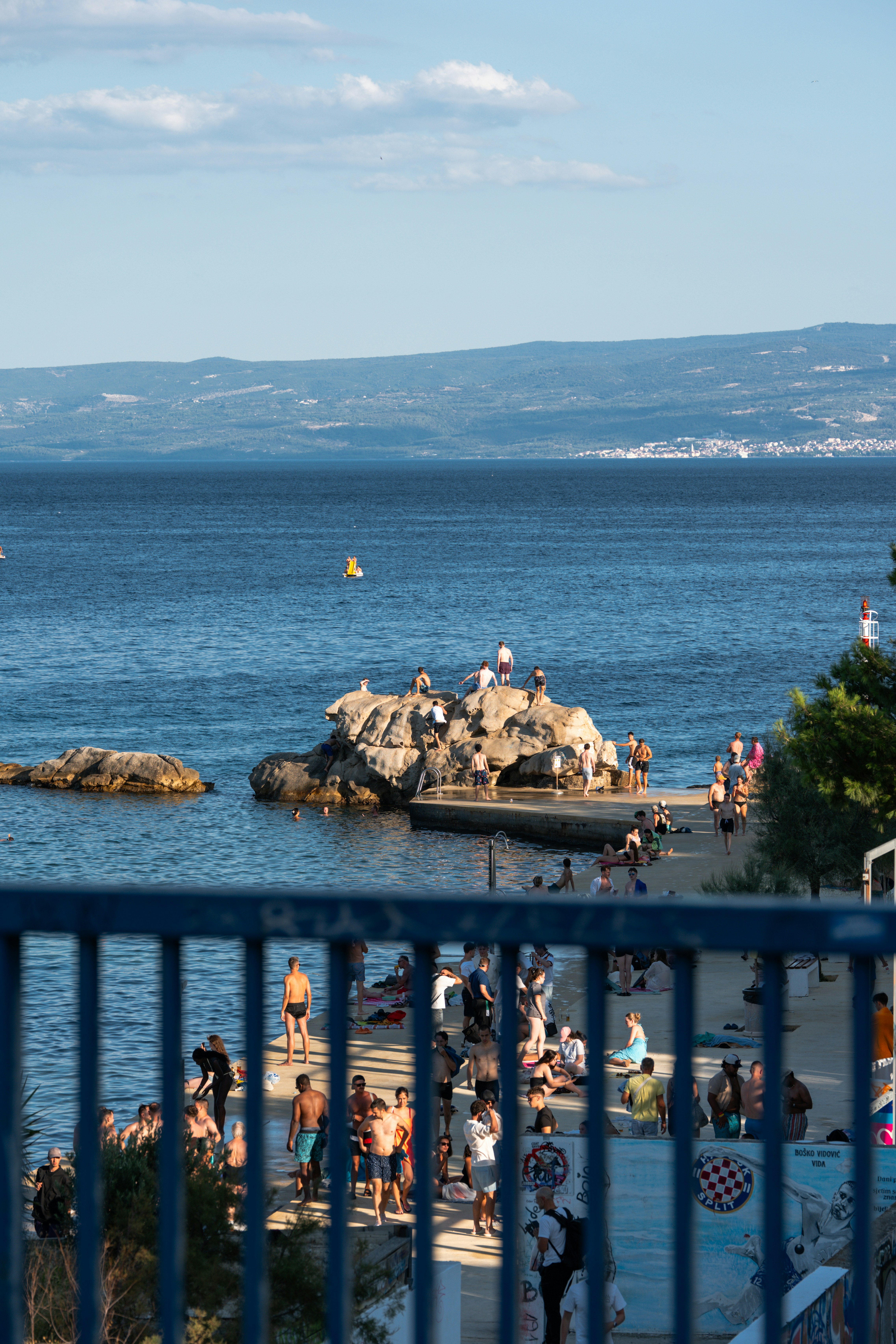 Sunlit Matter of the Sea: People on a Rock and Pier
