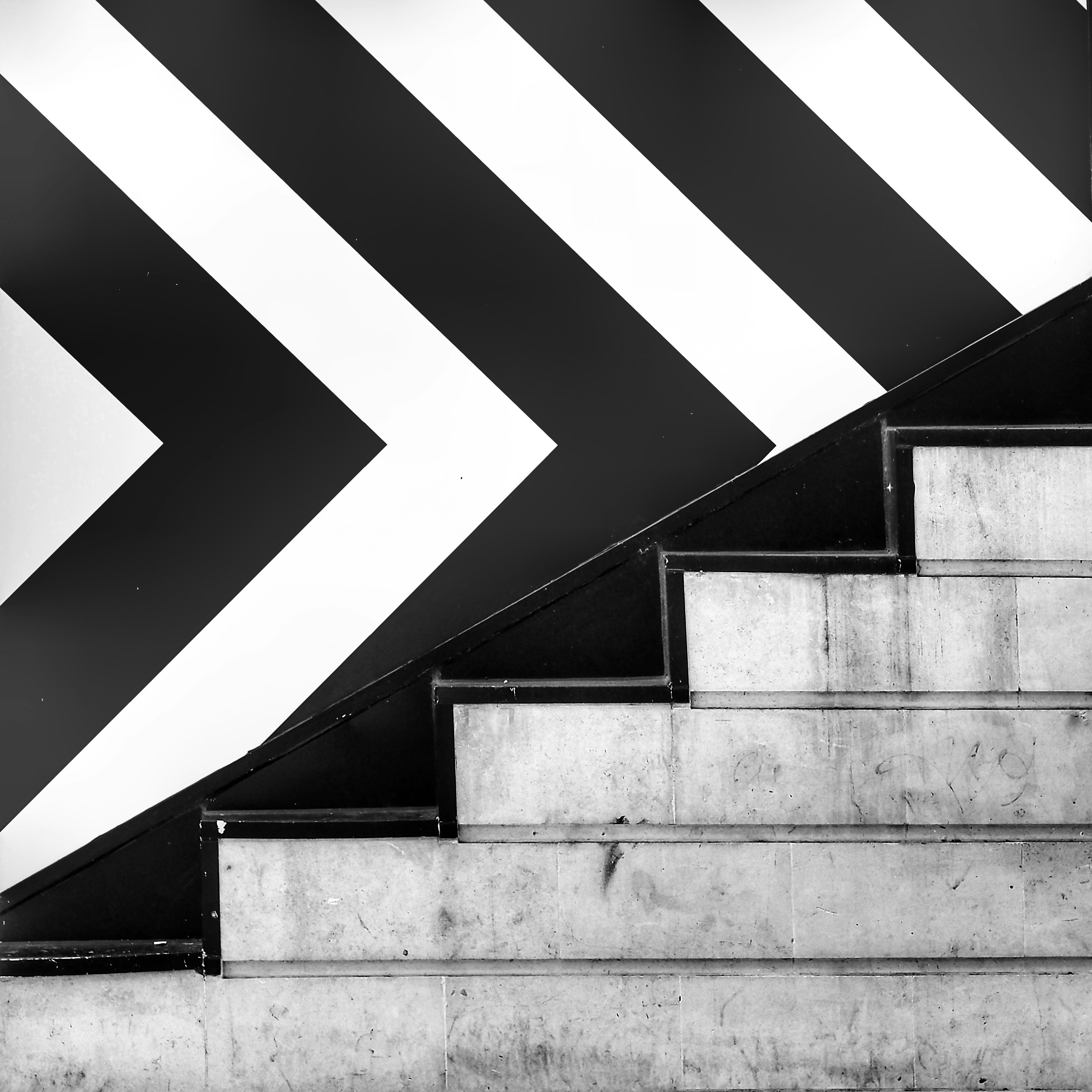 Geometric Ascent: Monochrome Stairs Meet a Chevron Wall