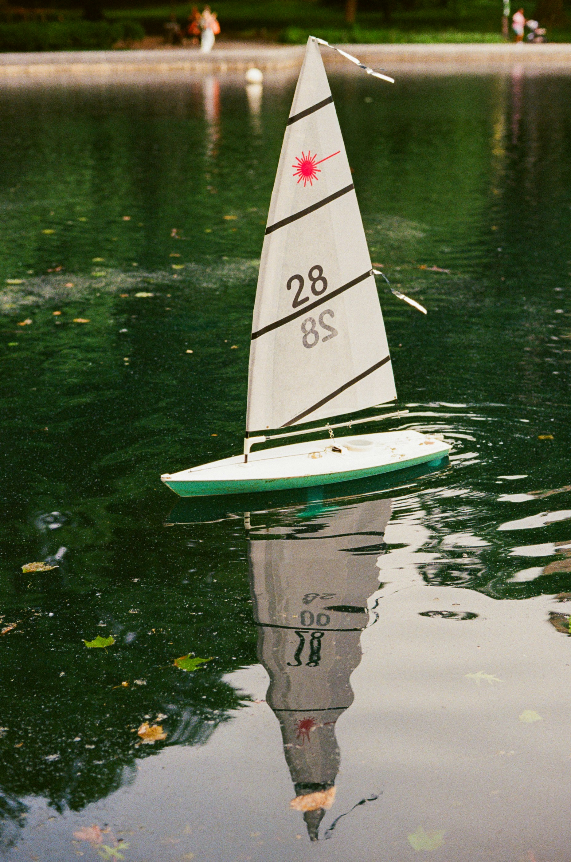Sailing Miniature: A Sailboat's Quiet Moment on a Reflective Pond