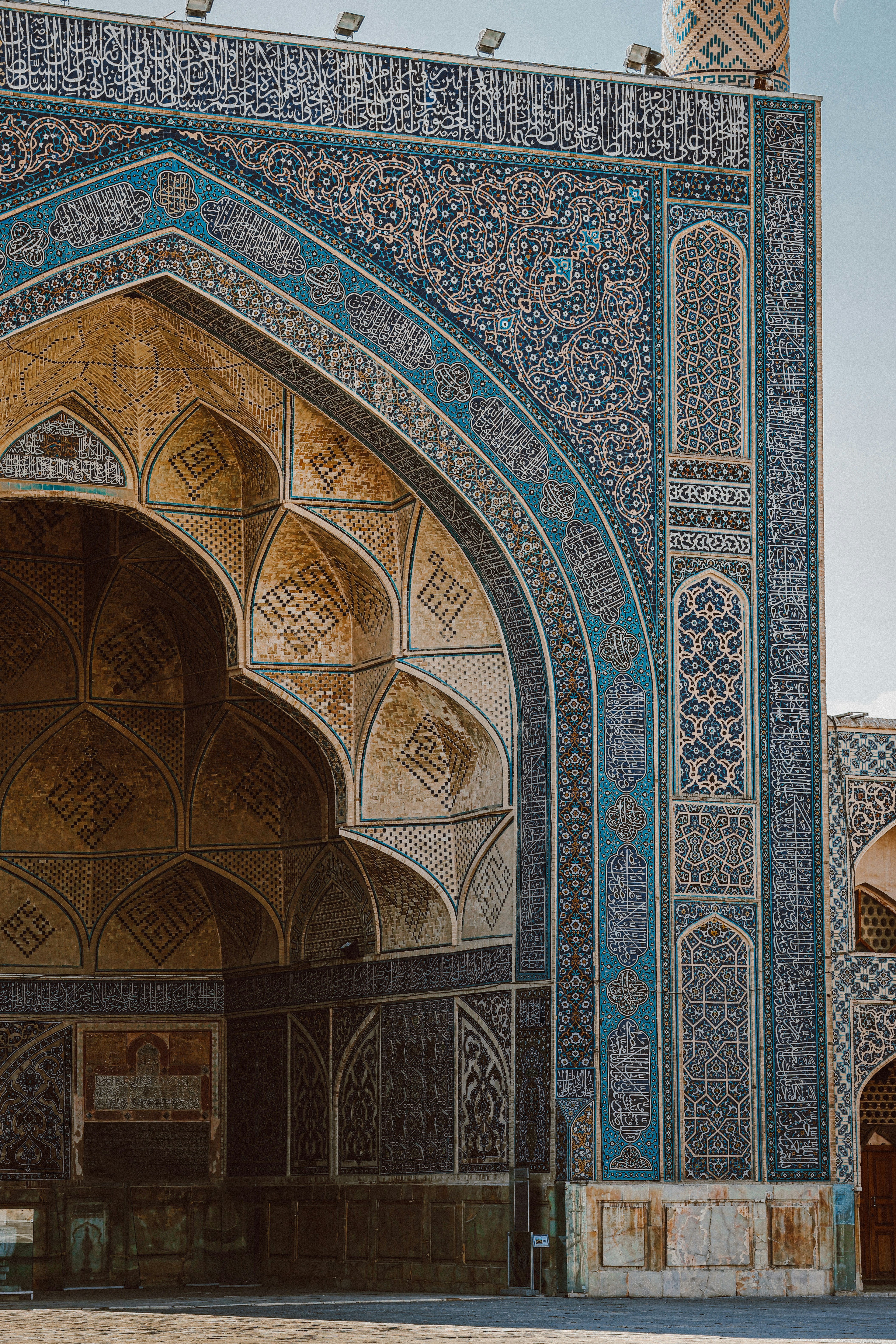 Detailed view of a mosque facade with elaborate blue tile mosaics and ornate archway, highlighting architectural decoration.