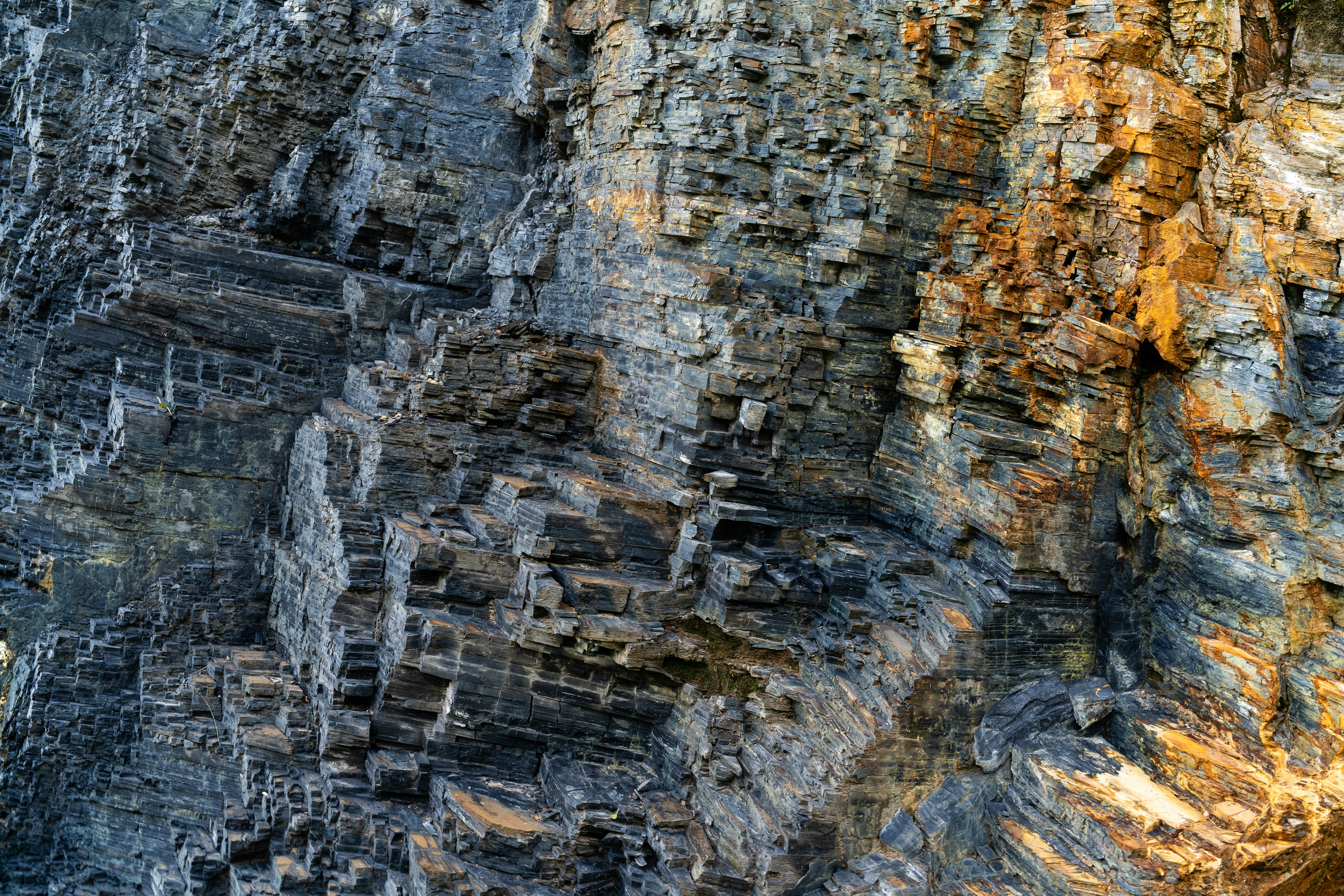 Geometric Faults: Interlocking Stone Facade in Sunlit Cliff Face