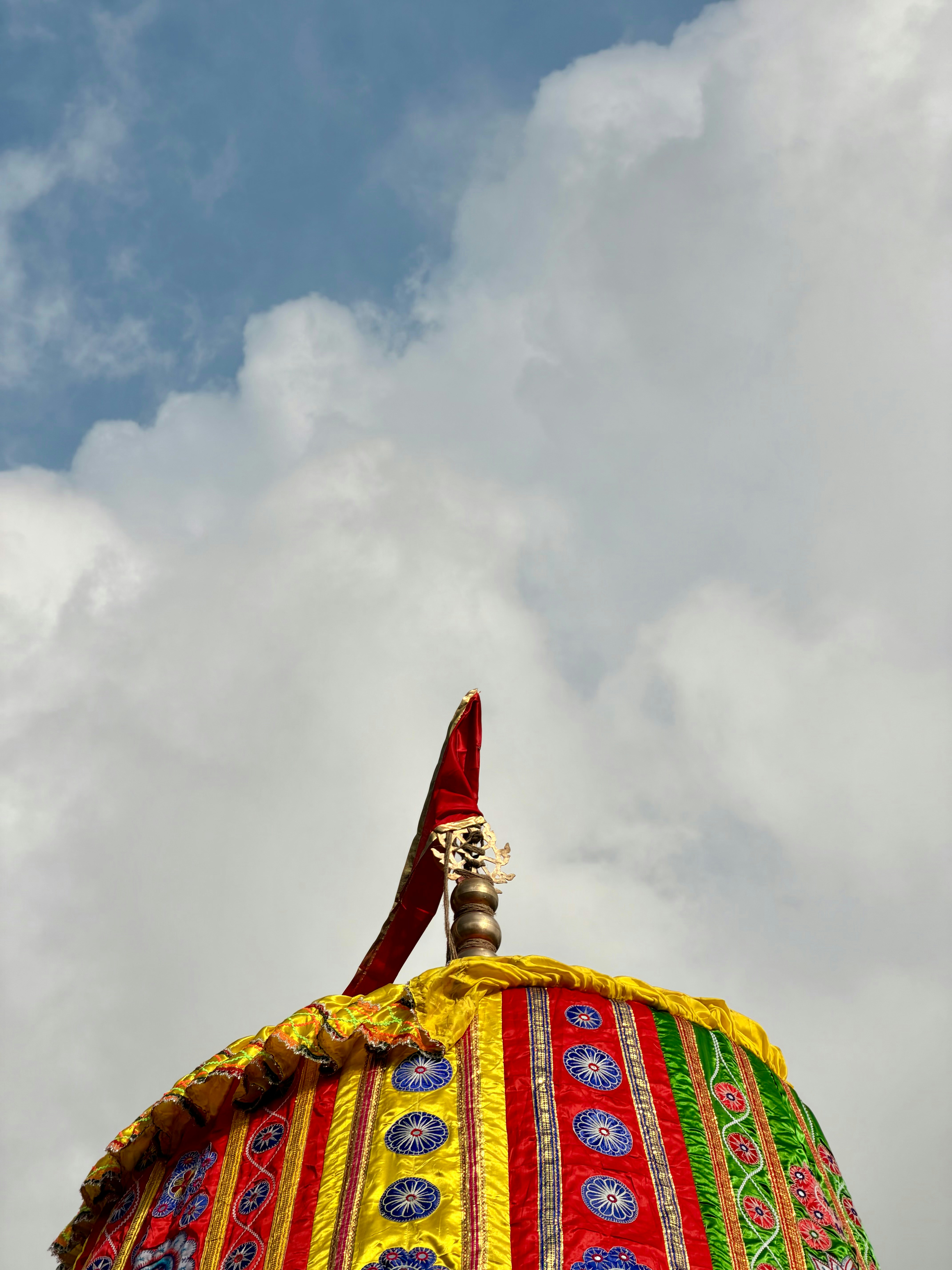 Colorful ceremonial canopy cresting against a cloudy sky