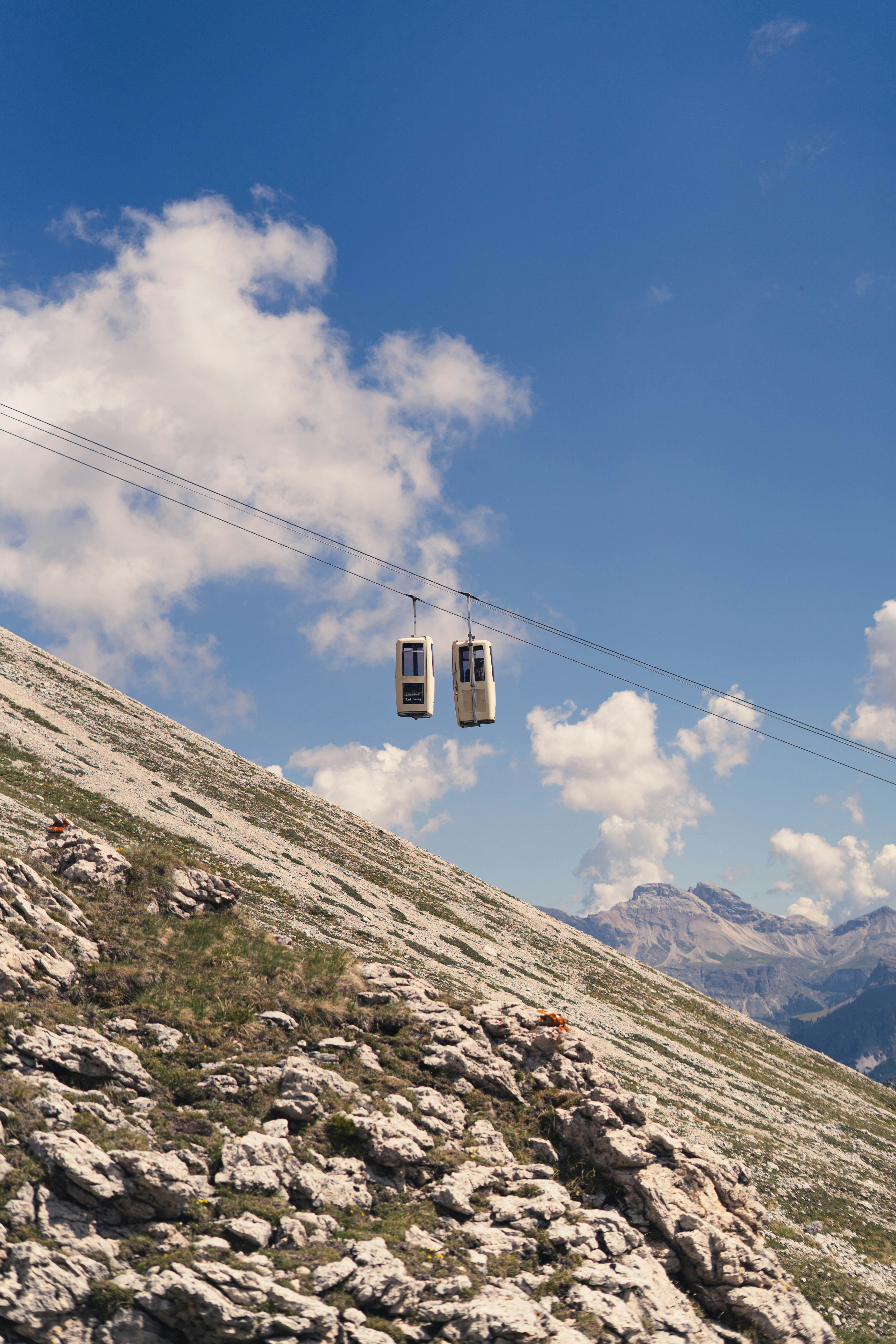 Suspended on the Mountain Ridge: Two Cable Cars Crossing a Sky-Blue Horizon