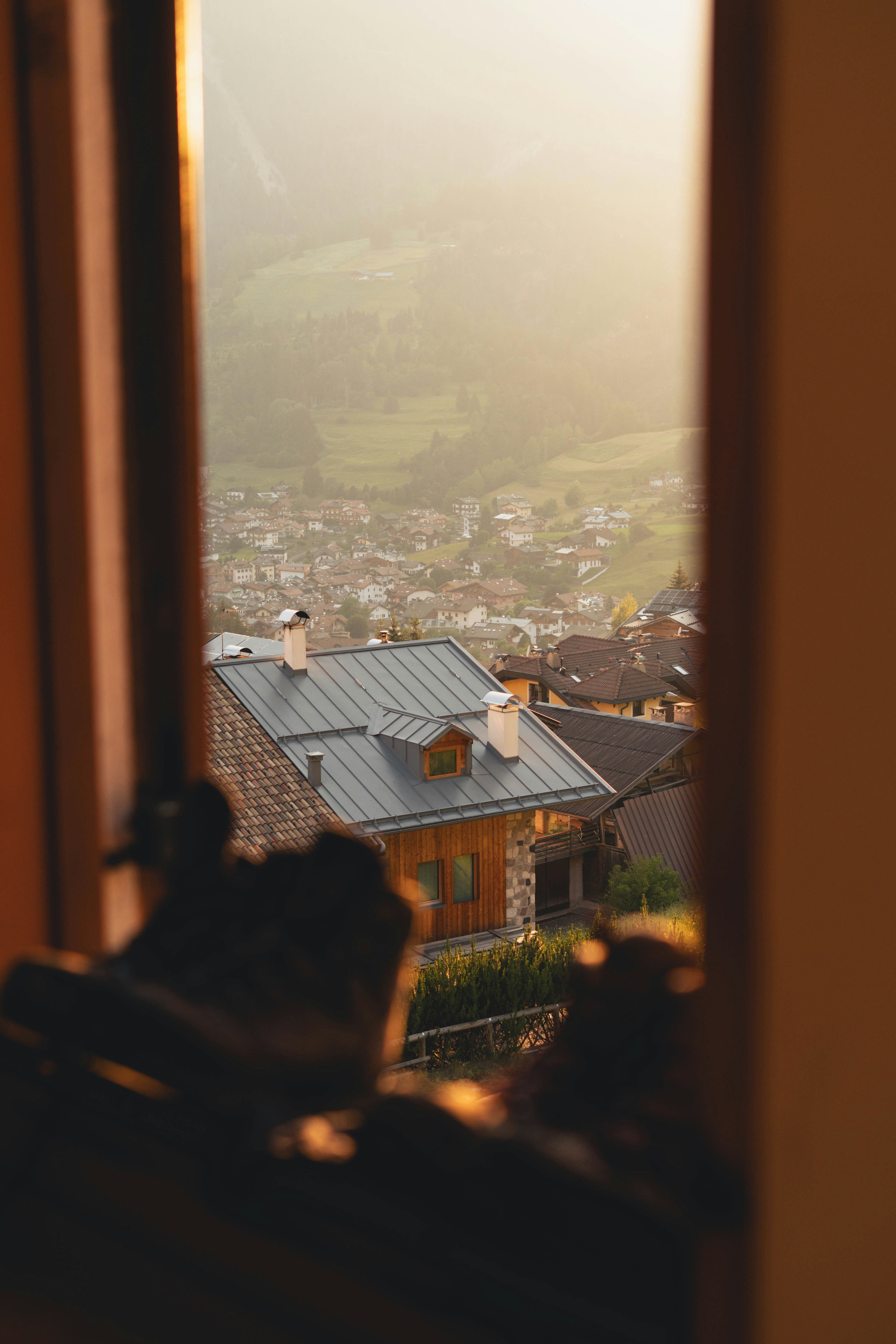 Through a Warm Window: A Quiet Mountain Village Framed by Interior Shadows