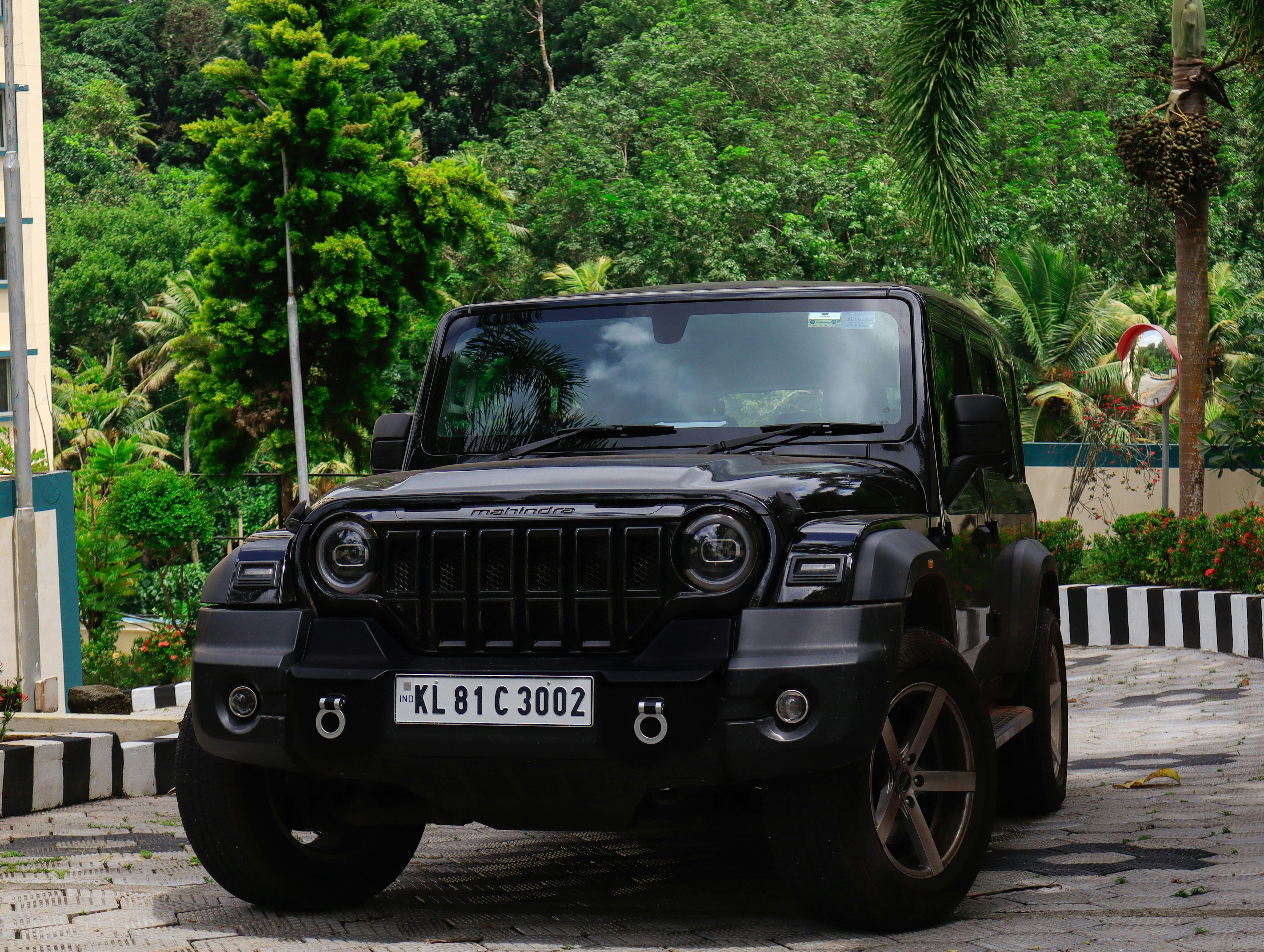 Dominant Black Off-Road Stance: Jeep in a Lush Driveway