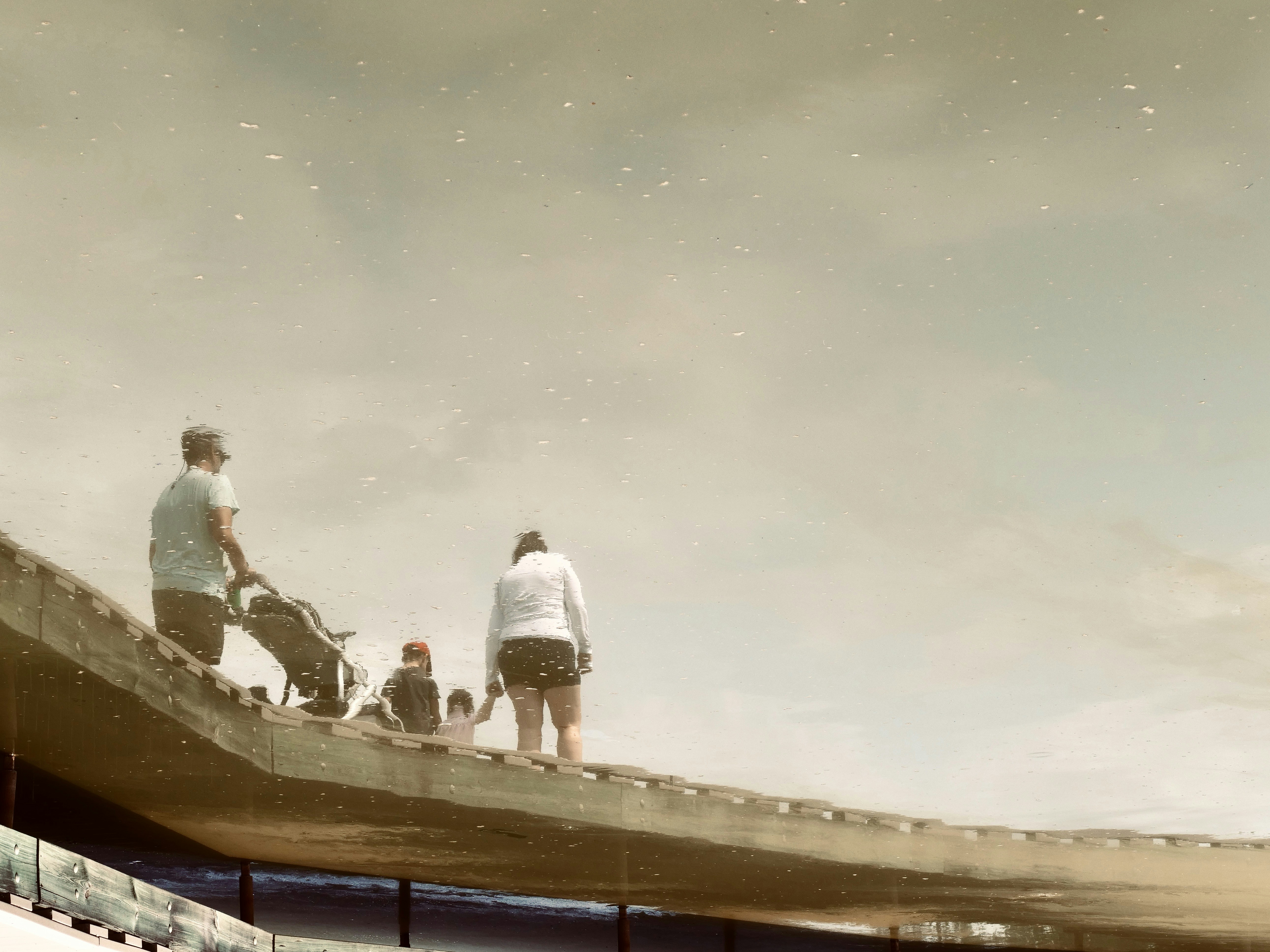 People on a sunlit boardwalk in a hazy, vintage-hued scene