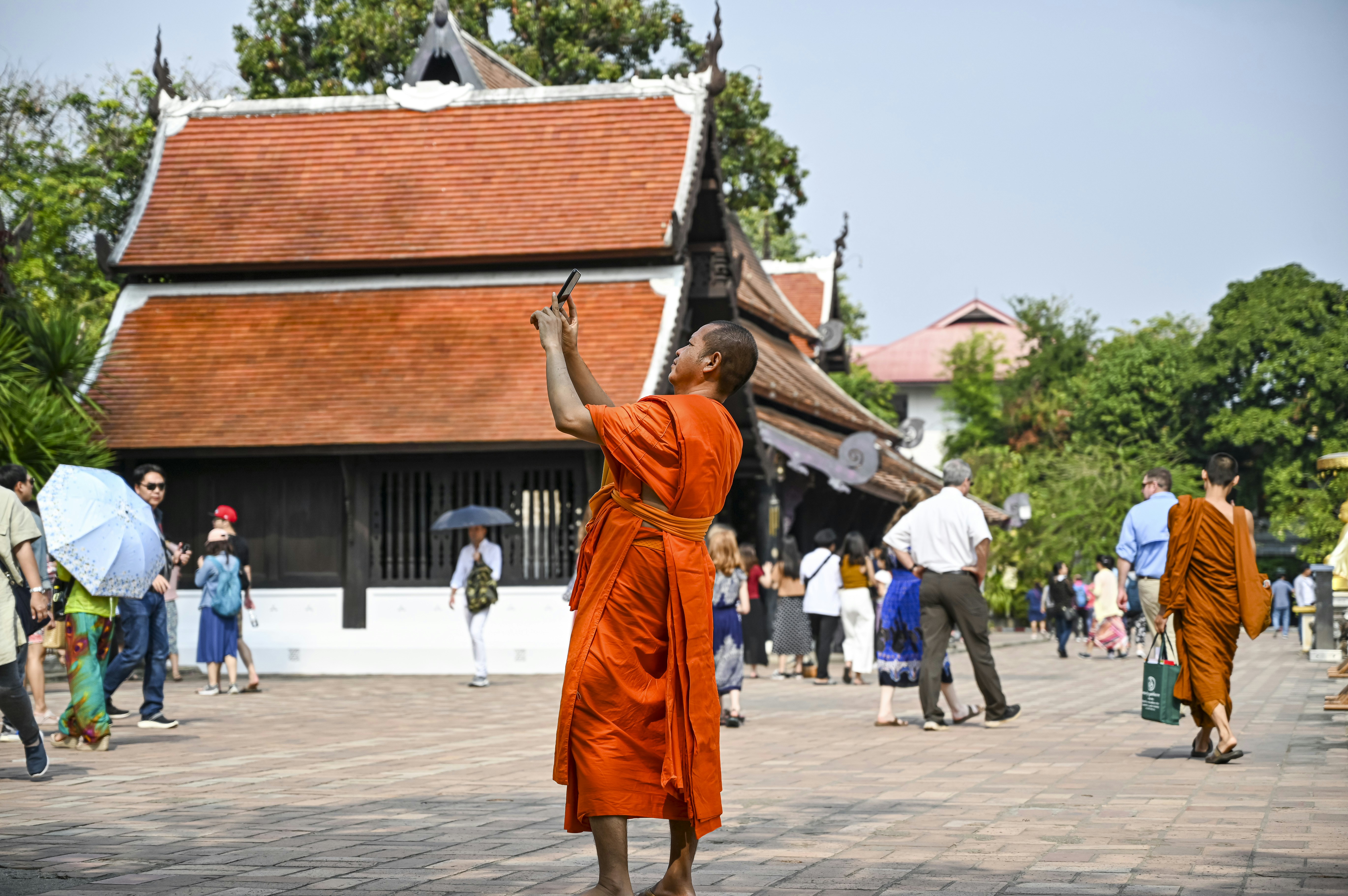 Orange Robe, Quiet Focus: A Monk Captures a Moment in the Temple Courtyard